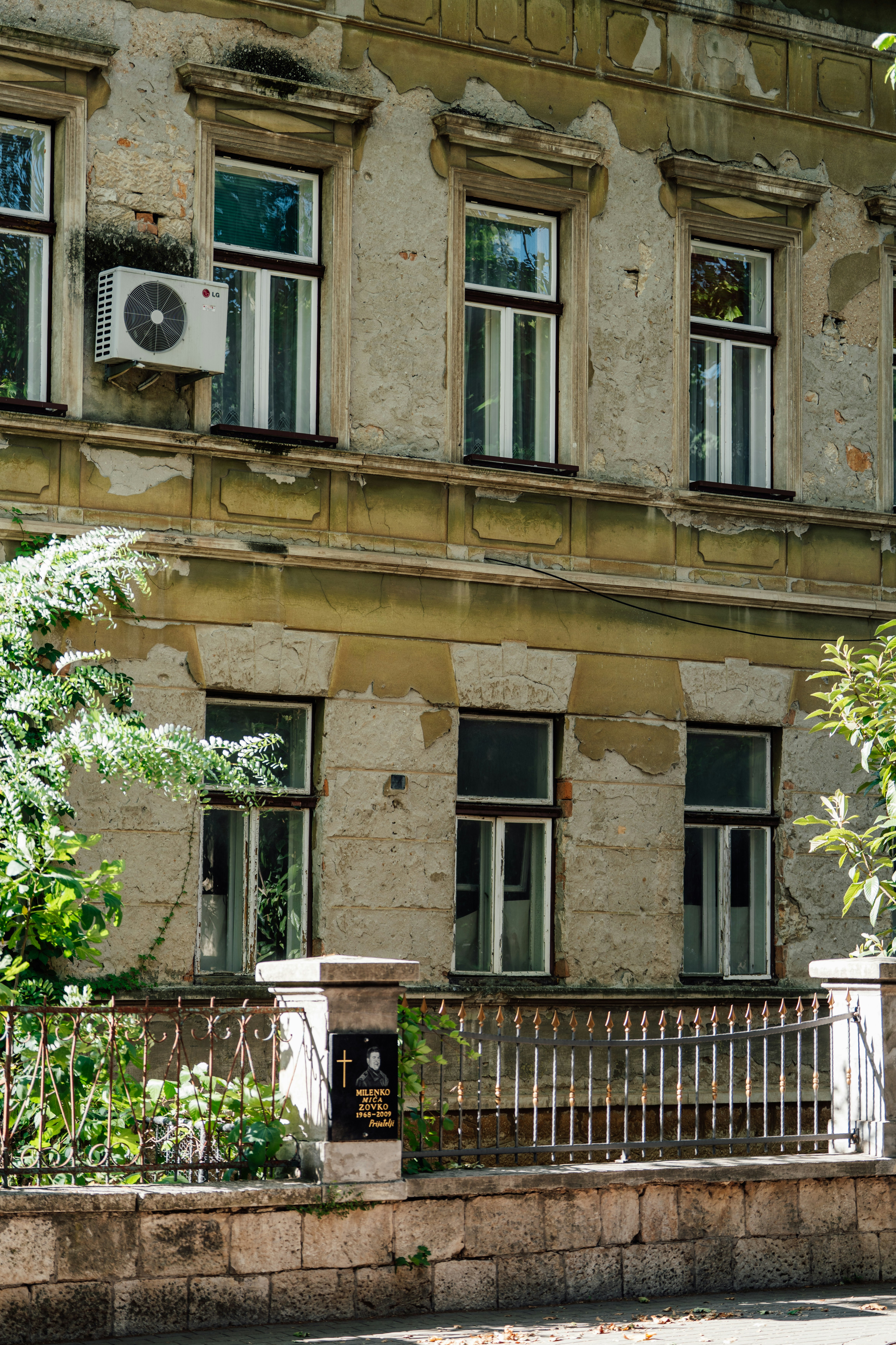 Weathered Facade and Quiet Courtyard: Greenery Framing an Old Building