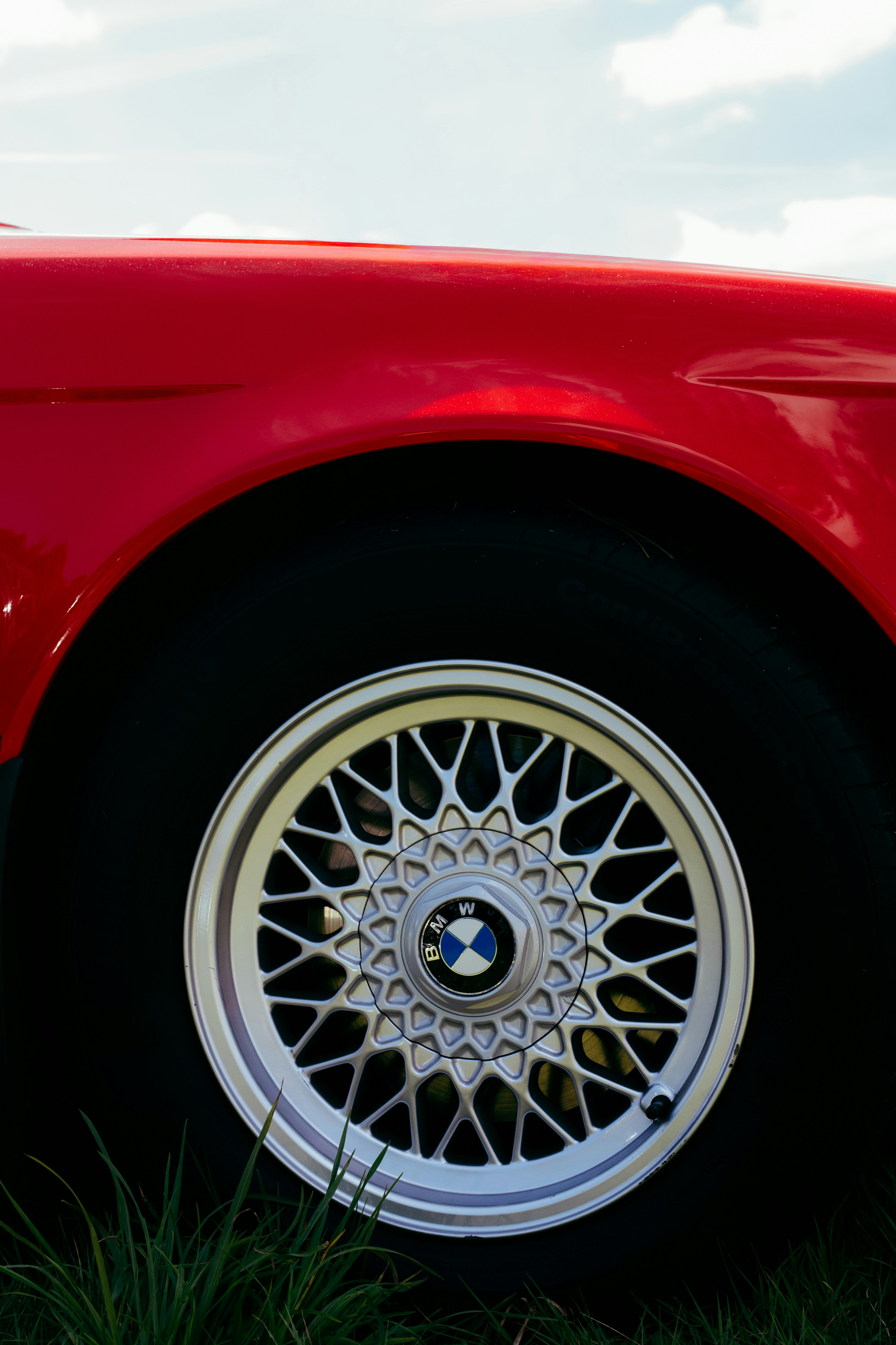Red Wheel, Quiet Focus: A Classic BMW Rim Framed by Red Bodywork