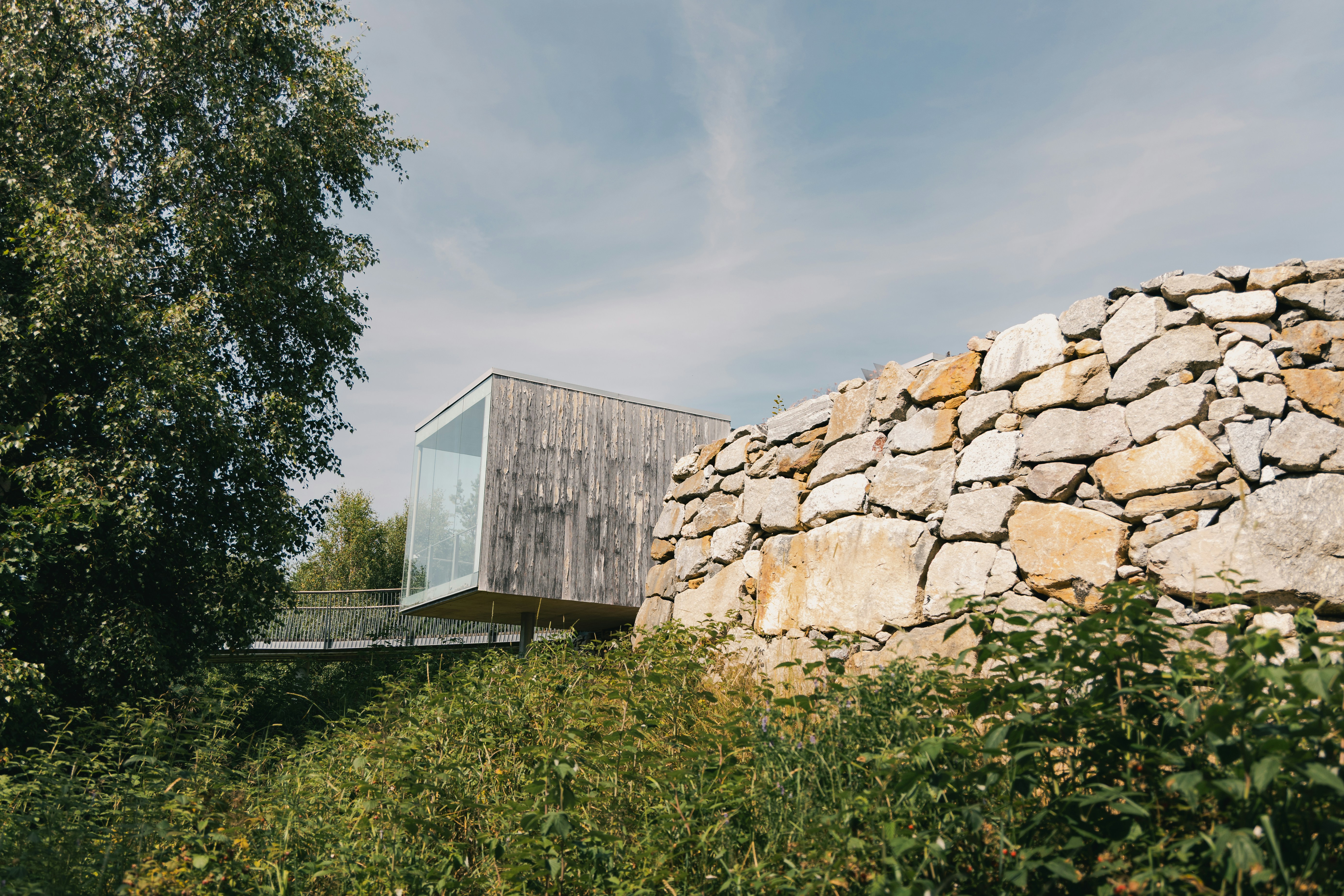 Concrete punctuated by stone: a modern glass box tucked beside a weathered wall