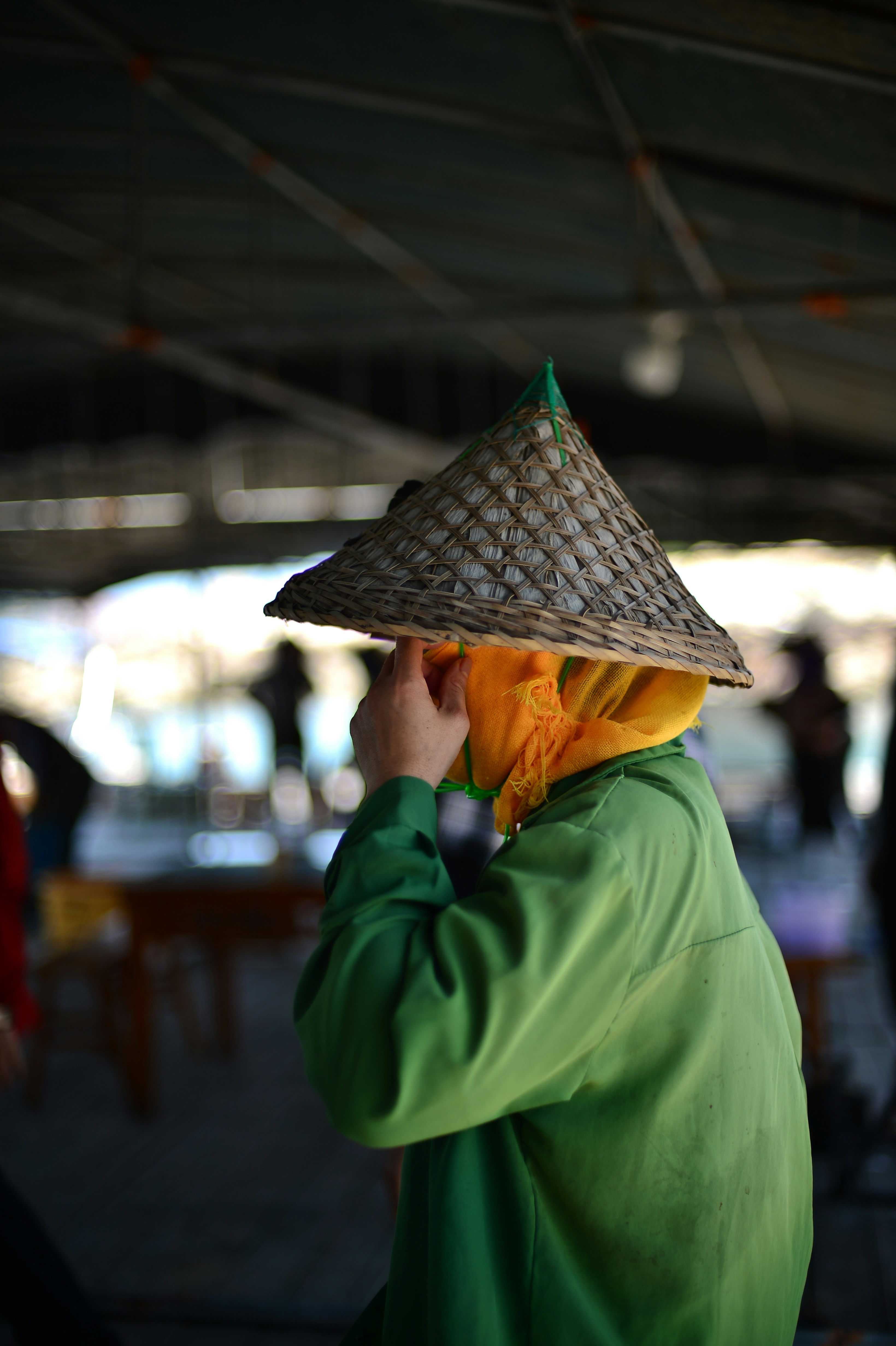 Conical hat and green cloak: a street portrait in soft focus