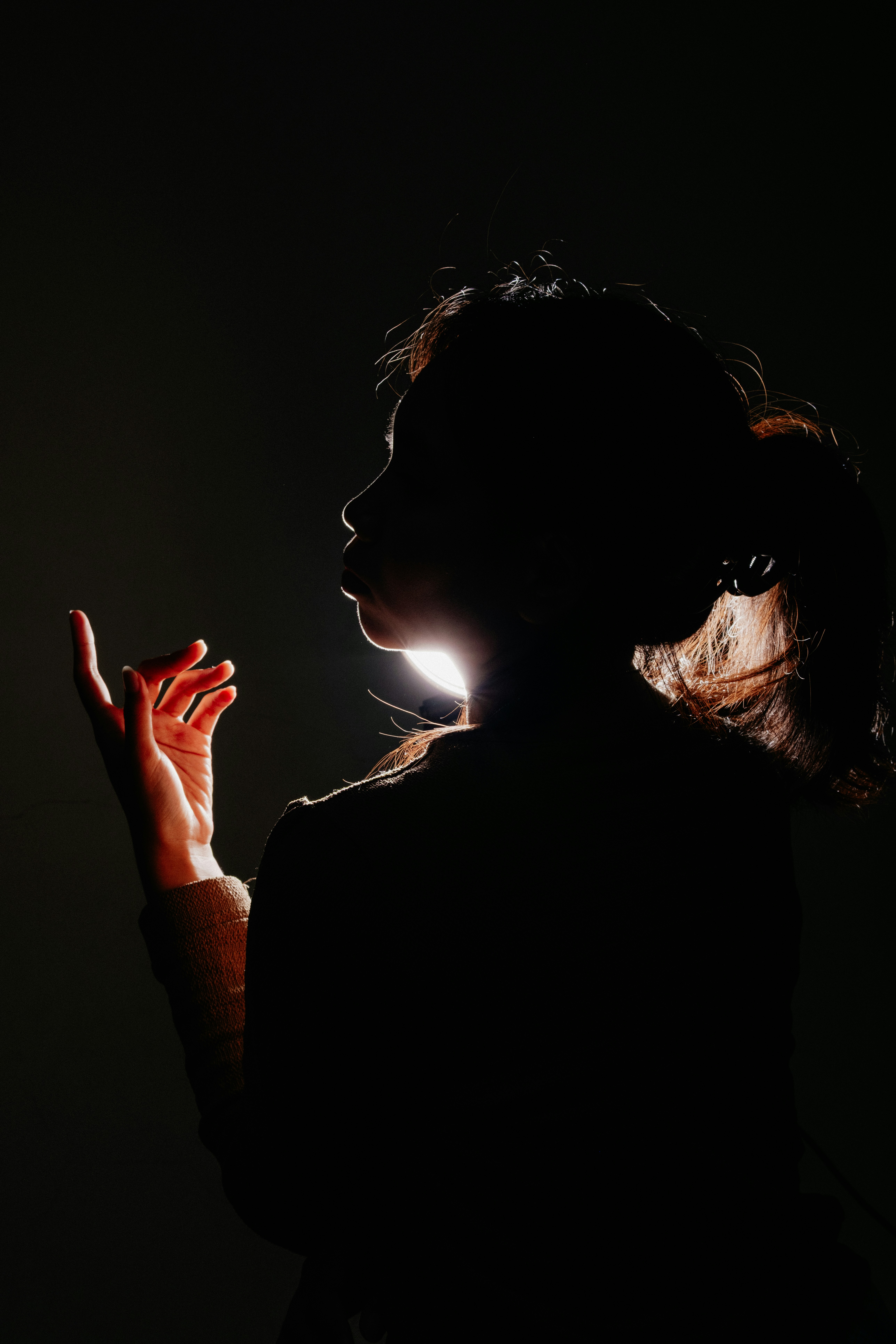 Backlit silhouette of a contemplative dancer in a dark studio