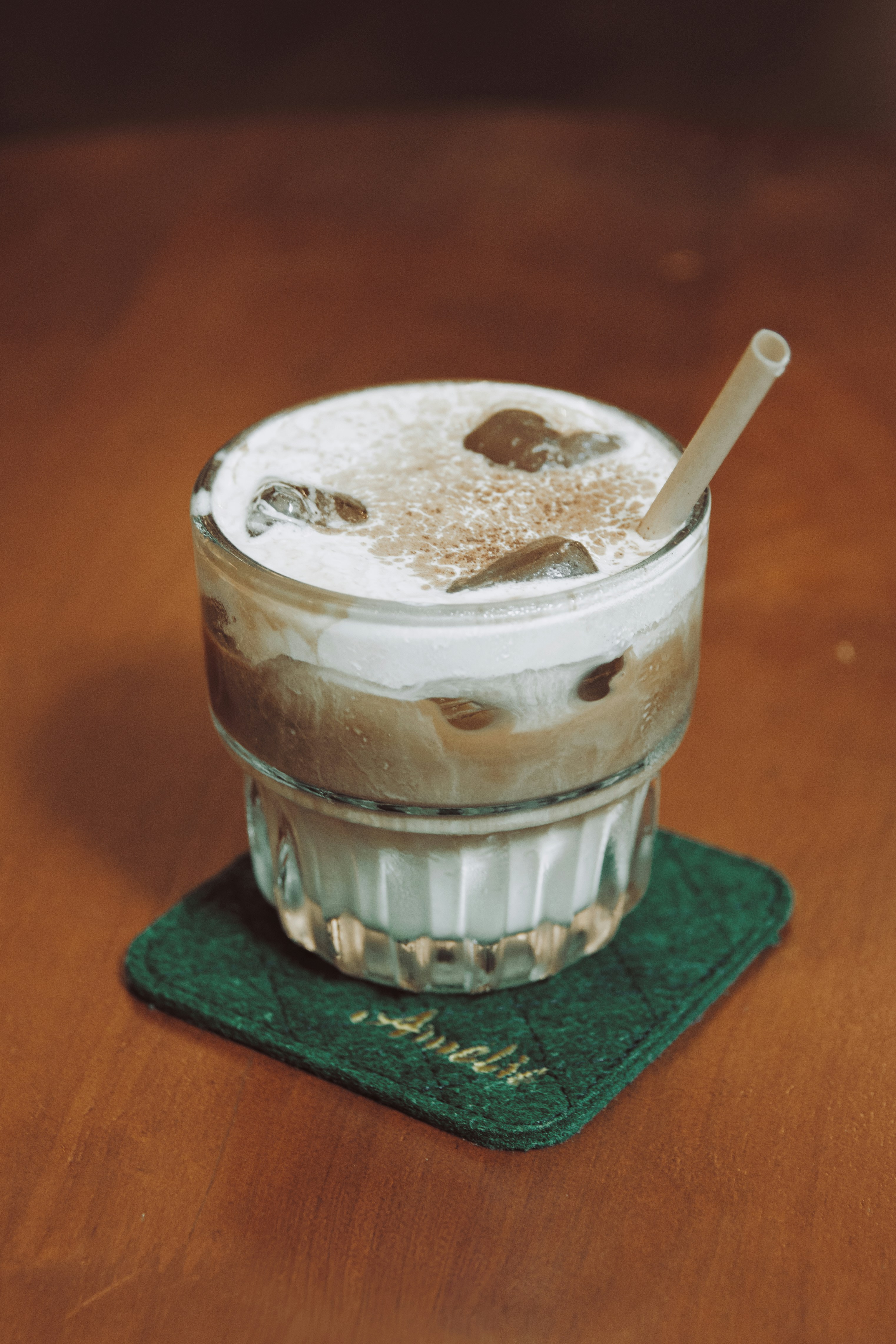 Creamy Sunrise: A Glass of Iced Coffee on a Wooden Bar