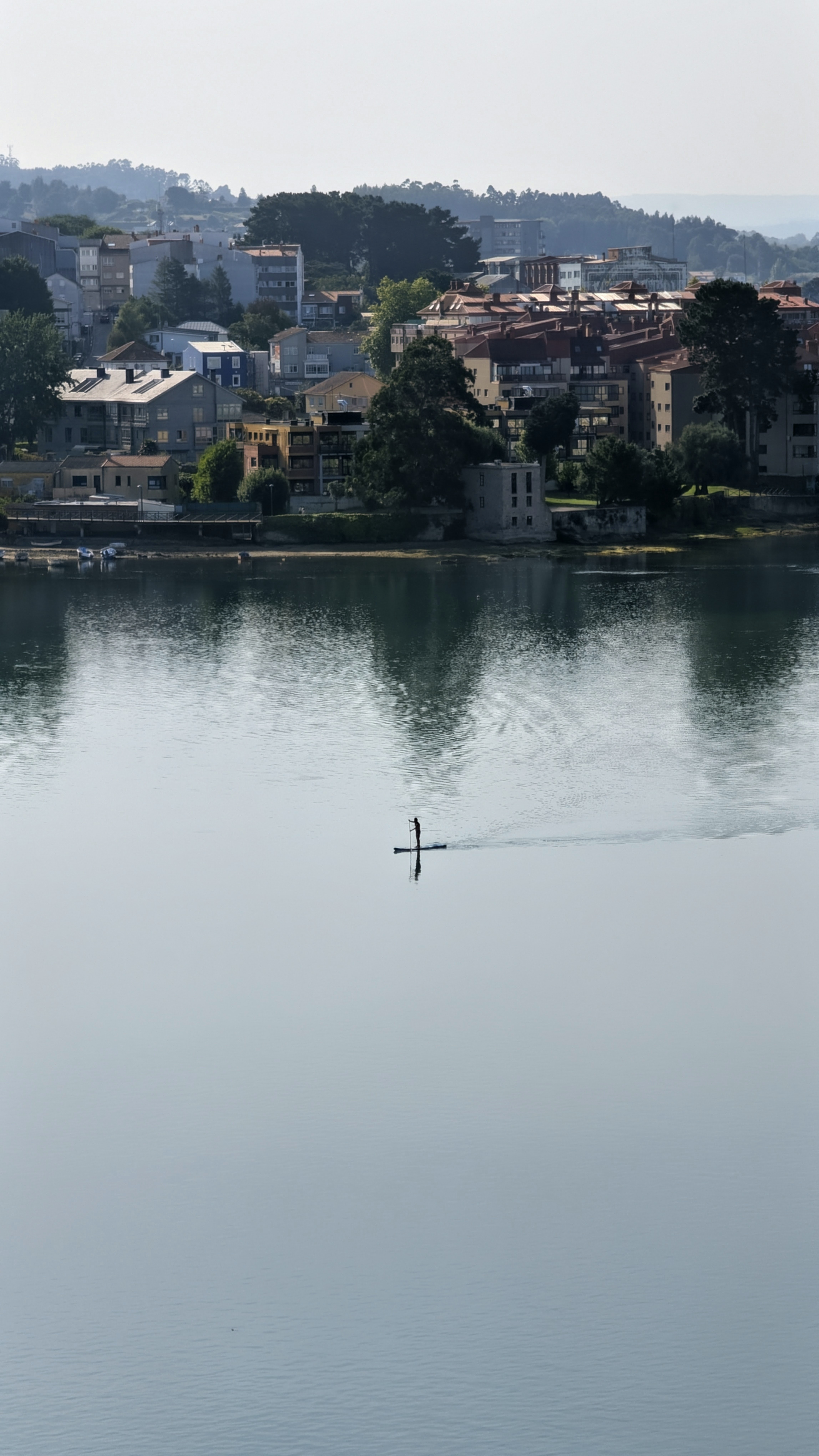 Lone Kayaker Silhouette on Quiet River Aiming Toward the Townline