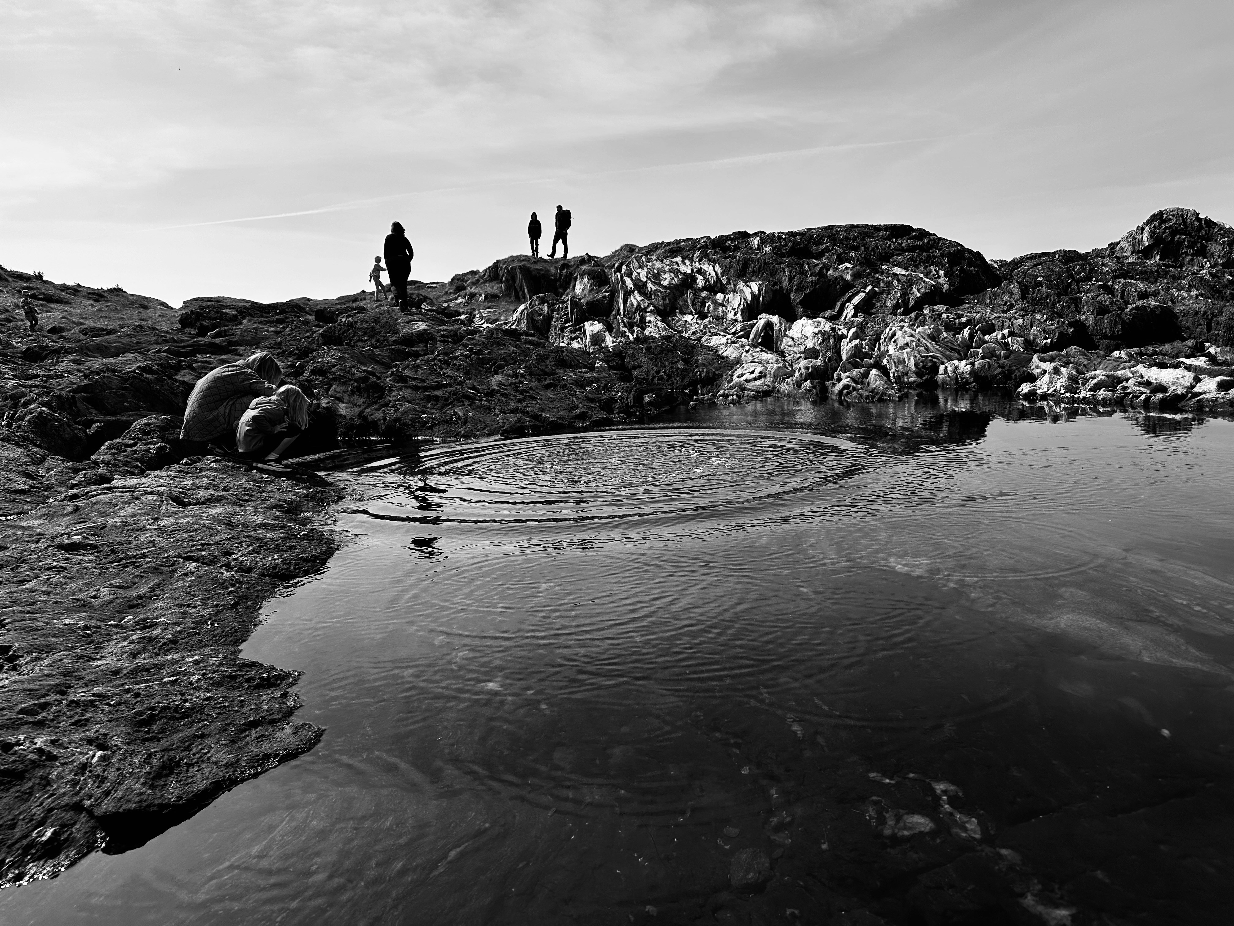 Quiet Tide: Figures at the Ridge Above a Circular Pool