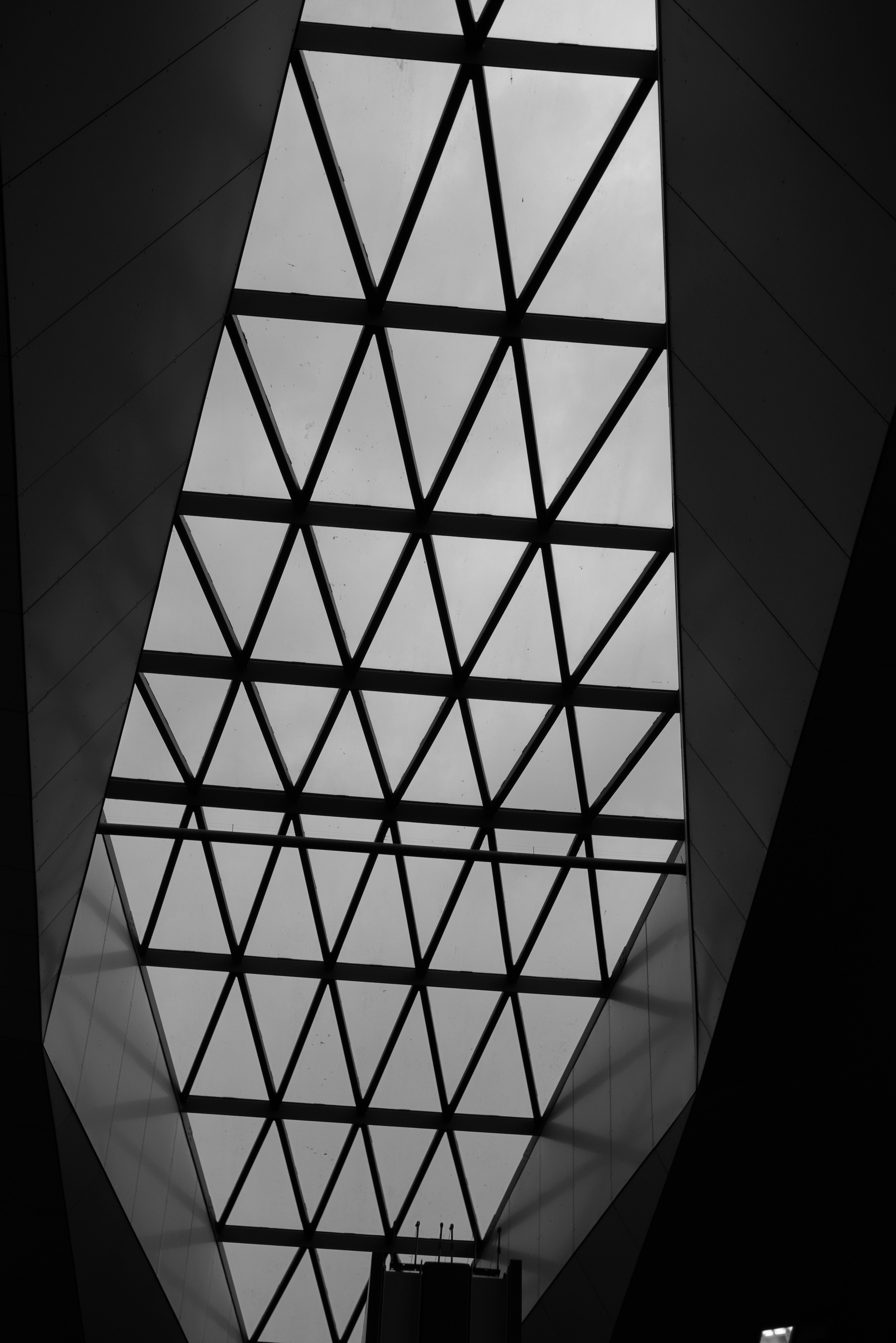 Geometric Glass Ceiling: A Monochrome Triangular Pattern Framed by Angled Walls