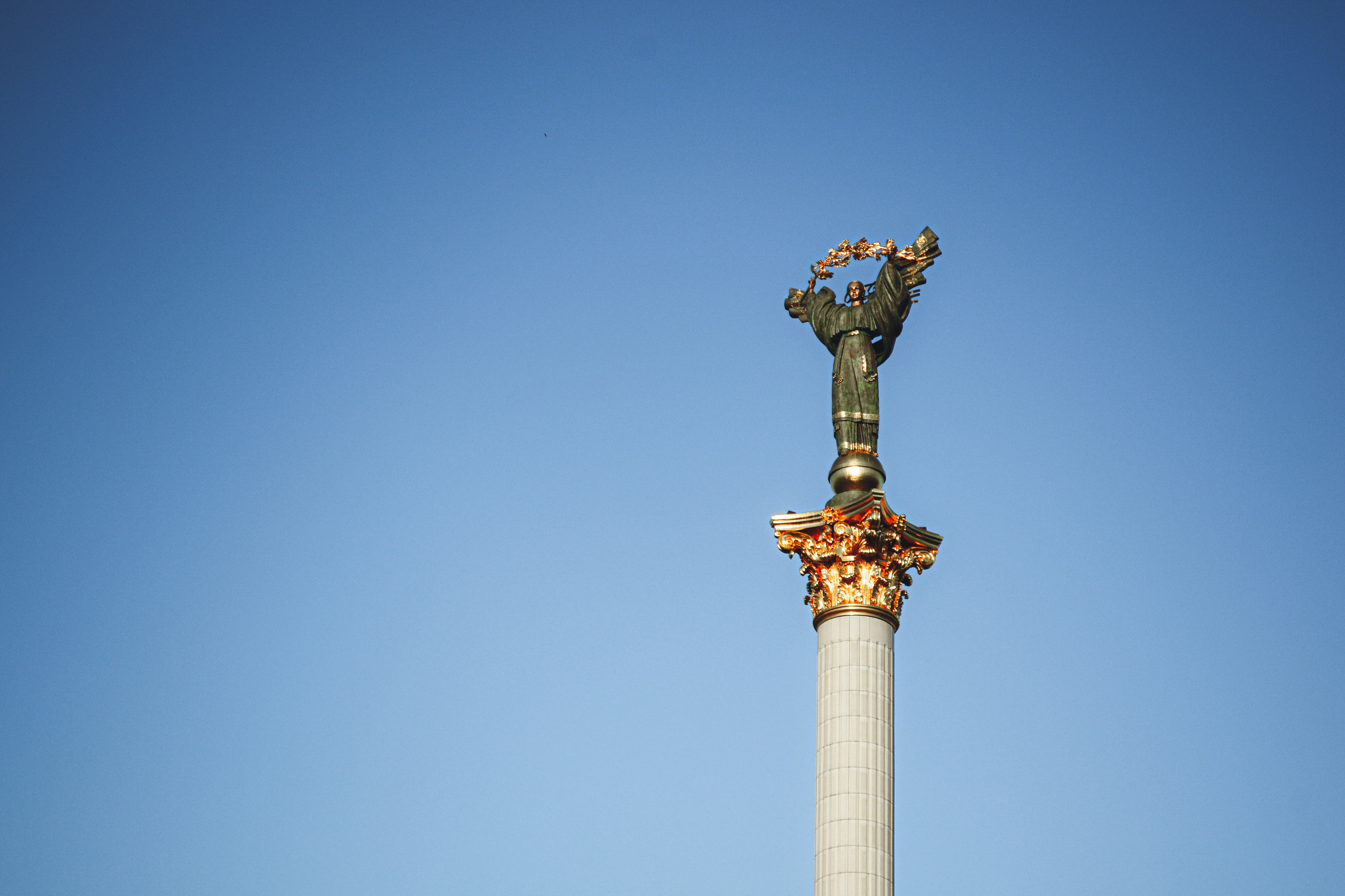Statue atop a tall column under a clear blue sky