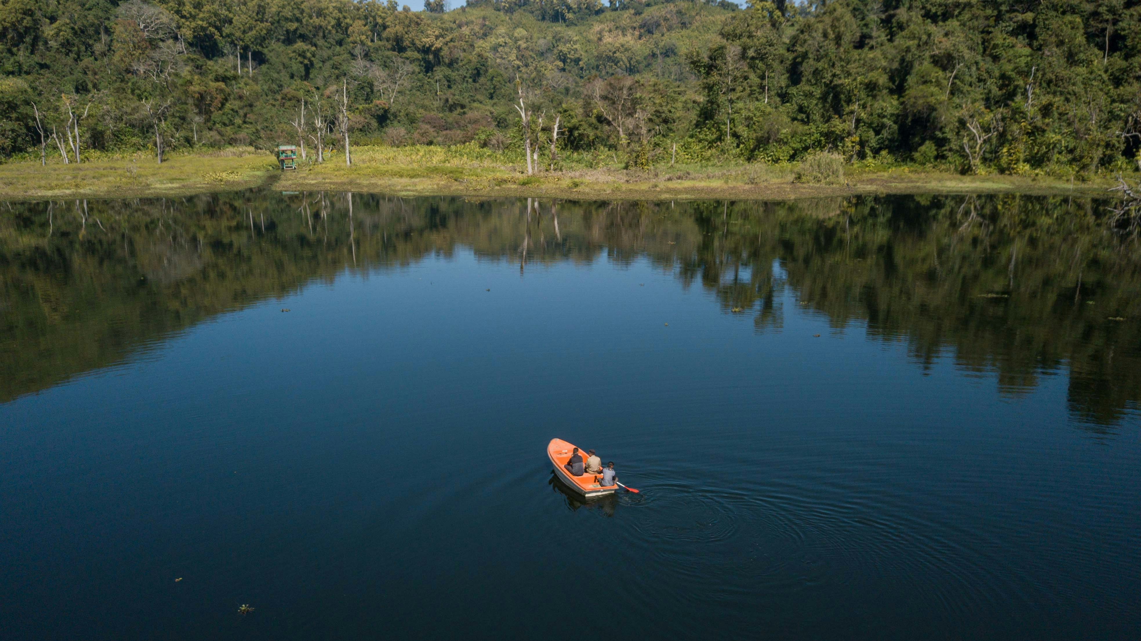 Quiet Dawn Over A Lake: lone orange boat on glassy water