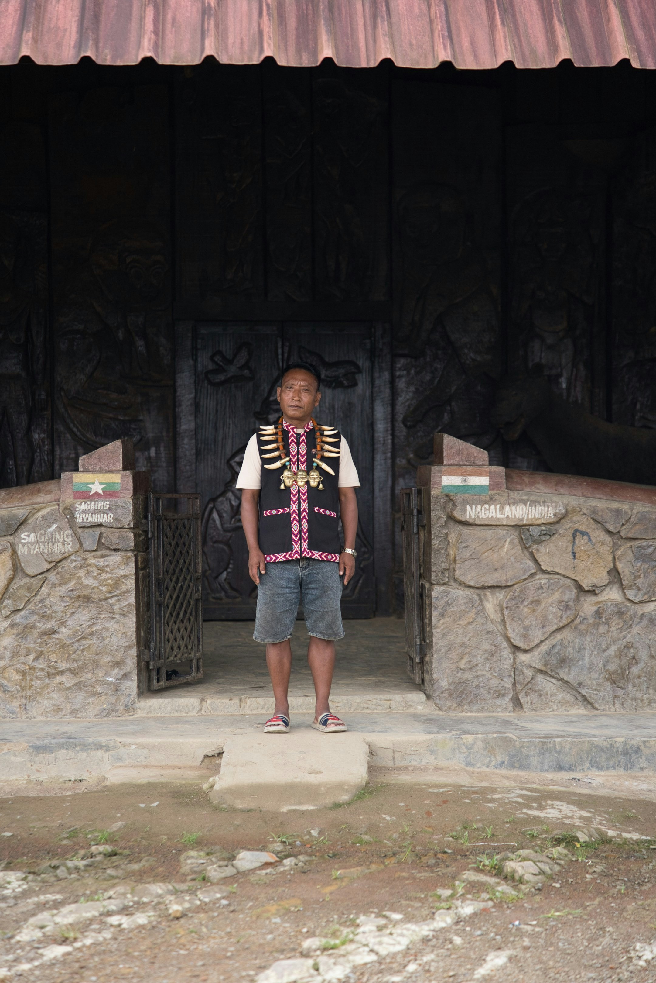 Guarded Entrance: A Traveler in Traditional Adornments Stands Before a Stone Facade