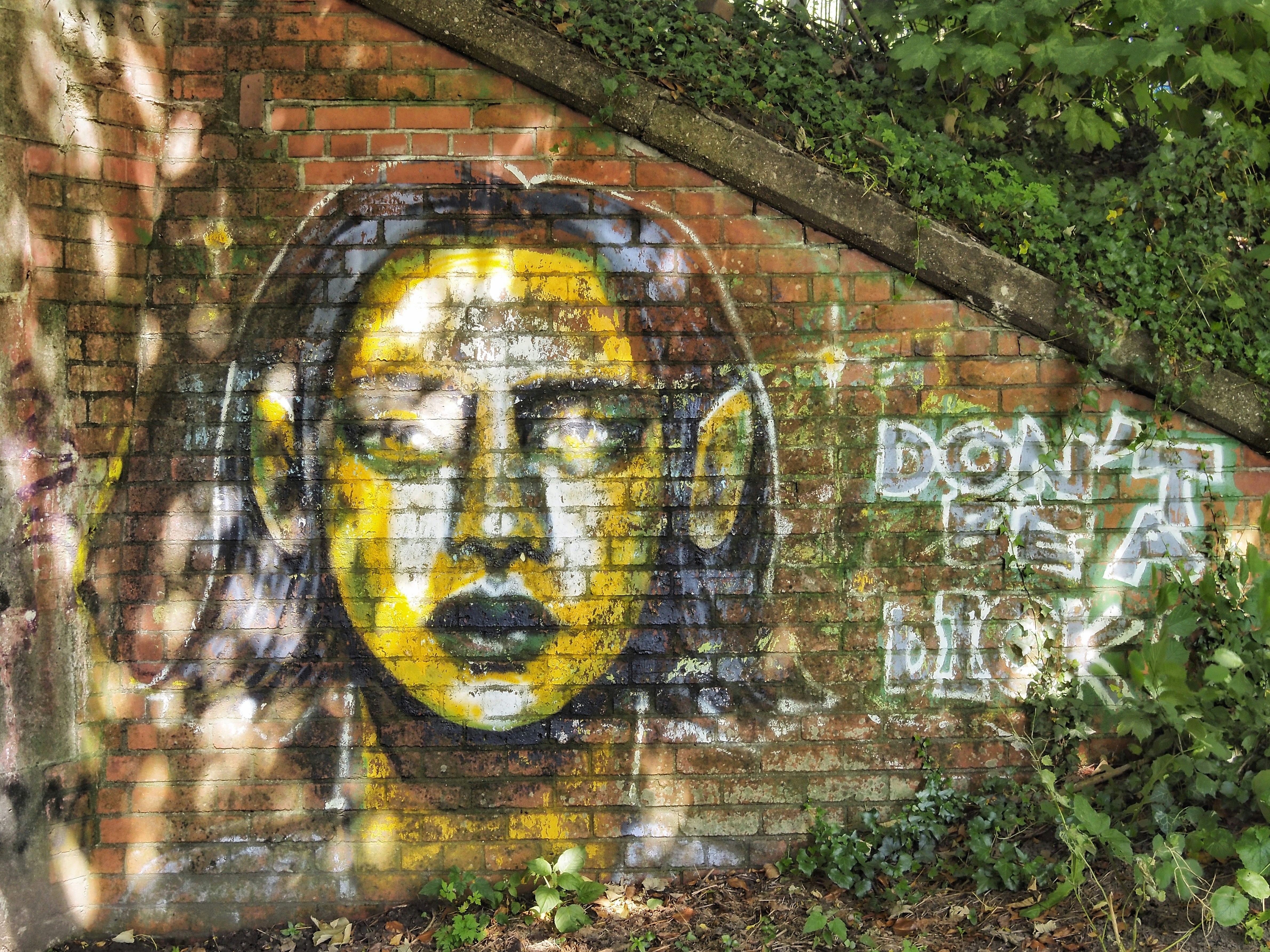 Yellow Mask on Bricked Wall: Graffiti Portrait by the Stairs