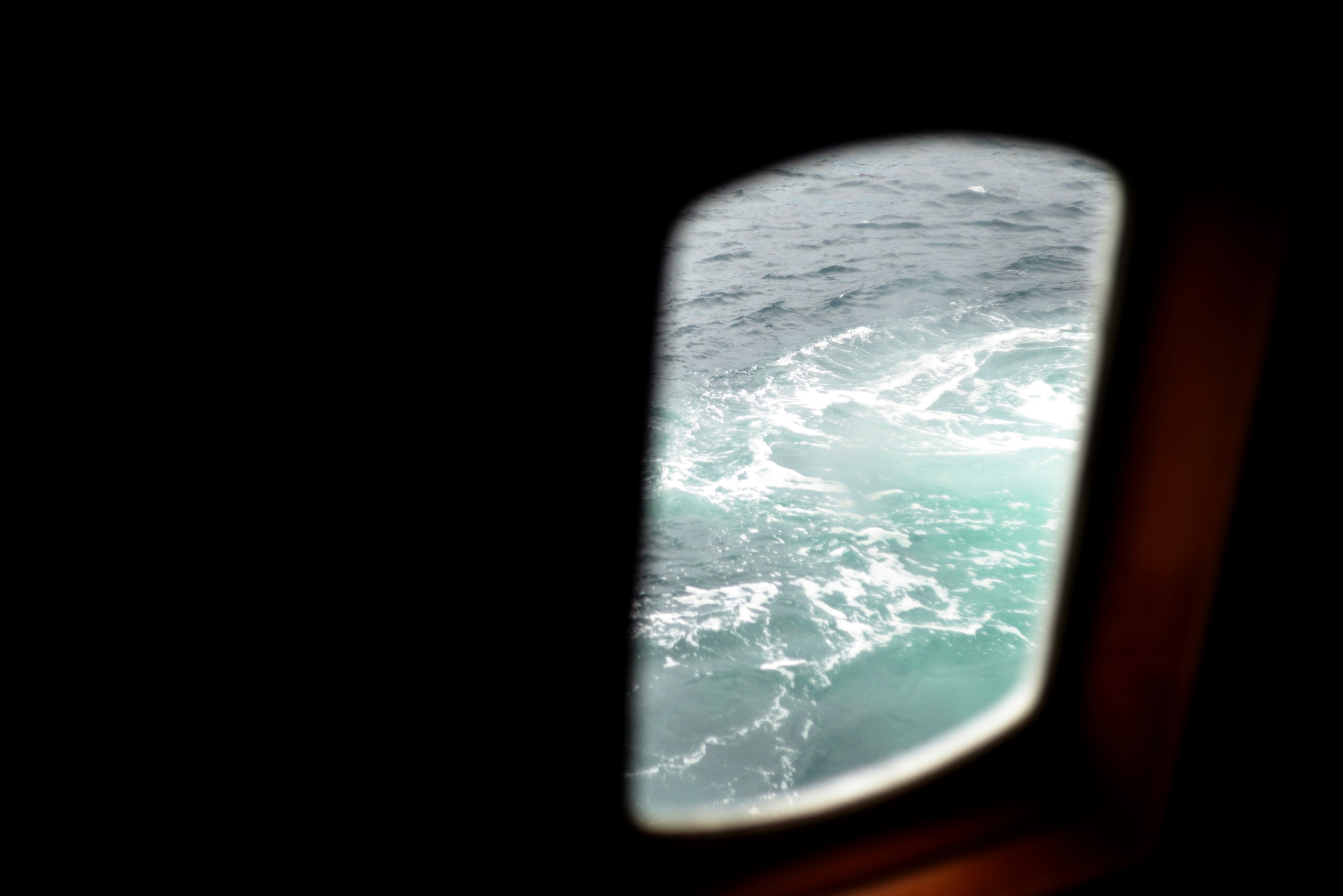 Sea Window: Turquoise Wake Through a Porthole