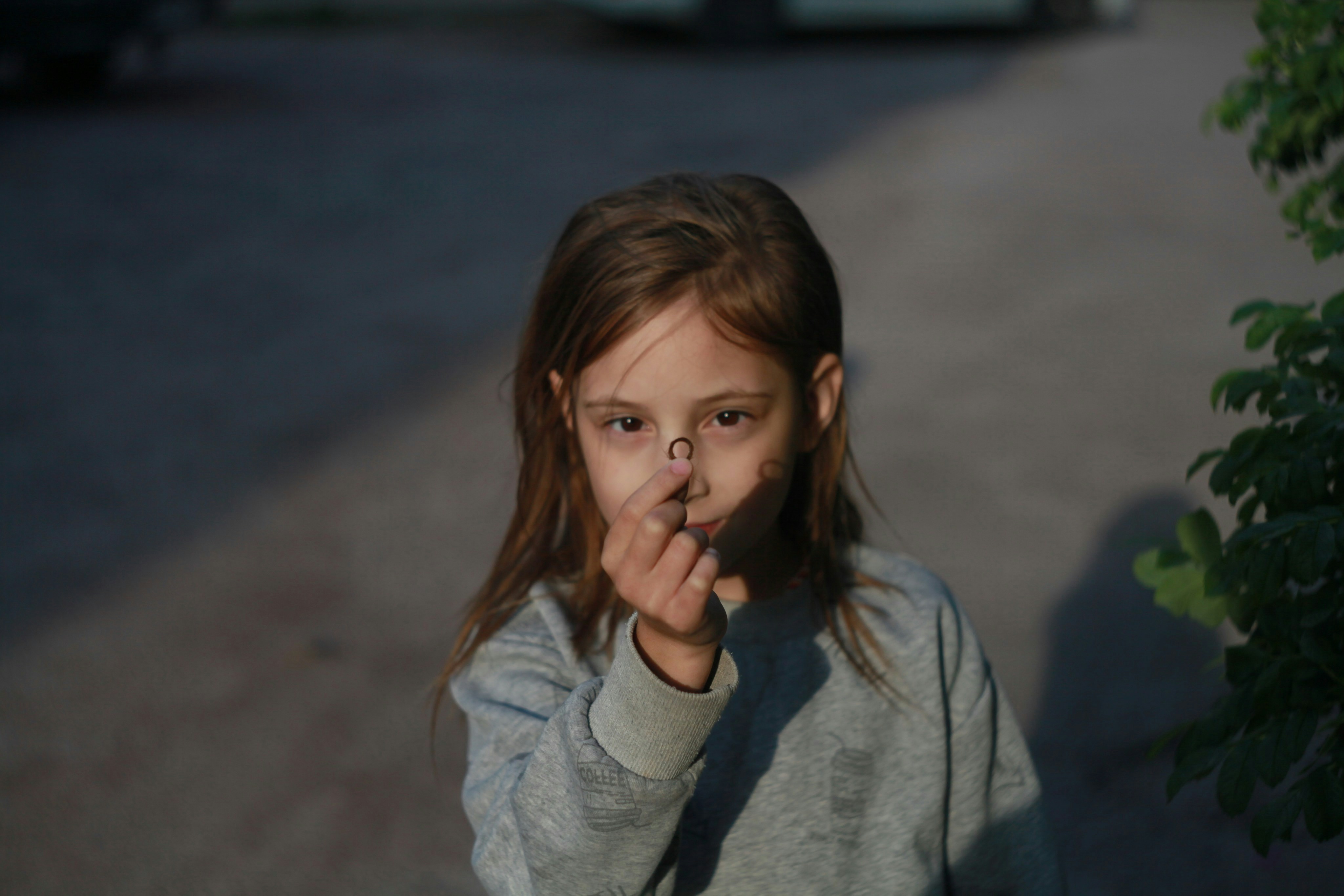 Girl with a Curious Gesture: A Quiet Moment in the Sunlit Street