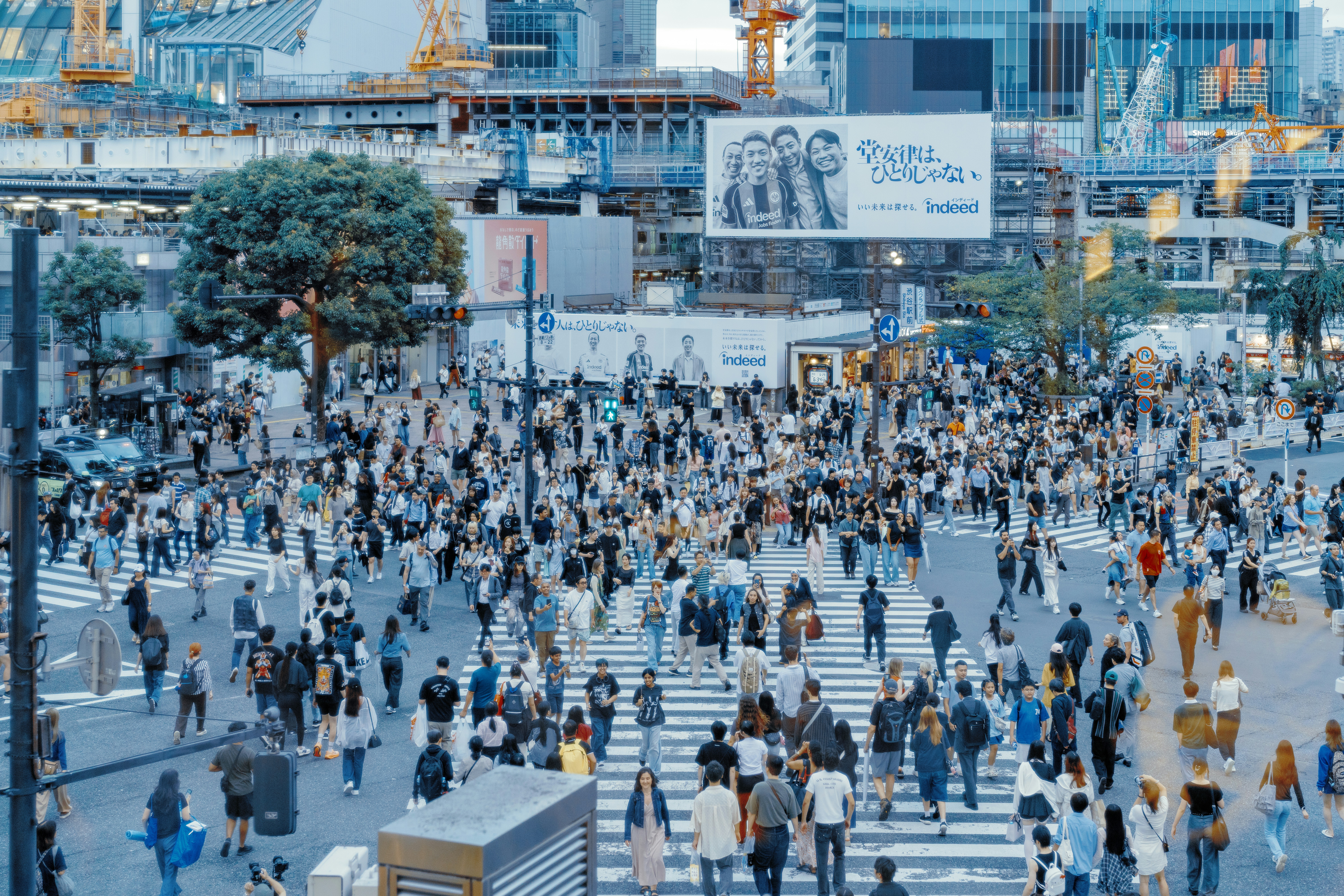 Crosswalk Nexus: A Sea of City Life Beneath Construction Skies