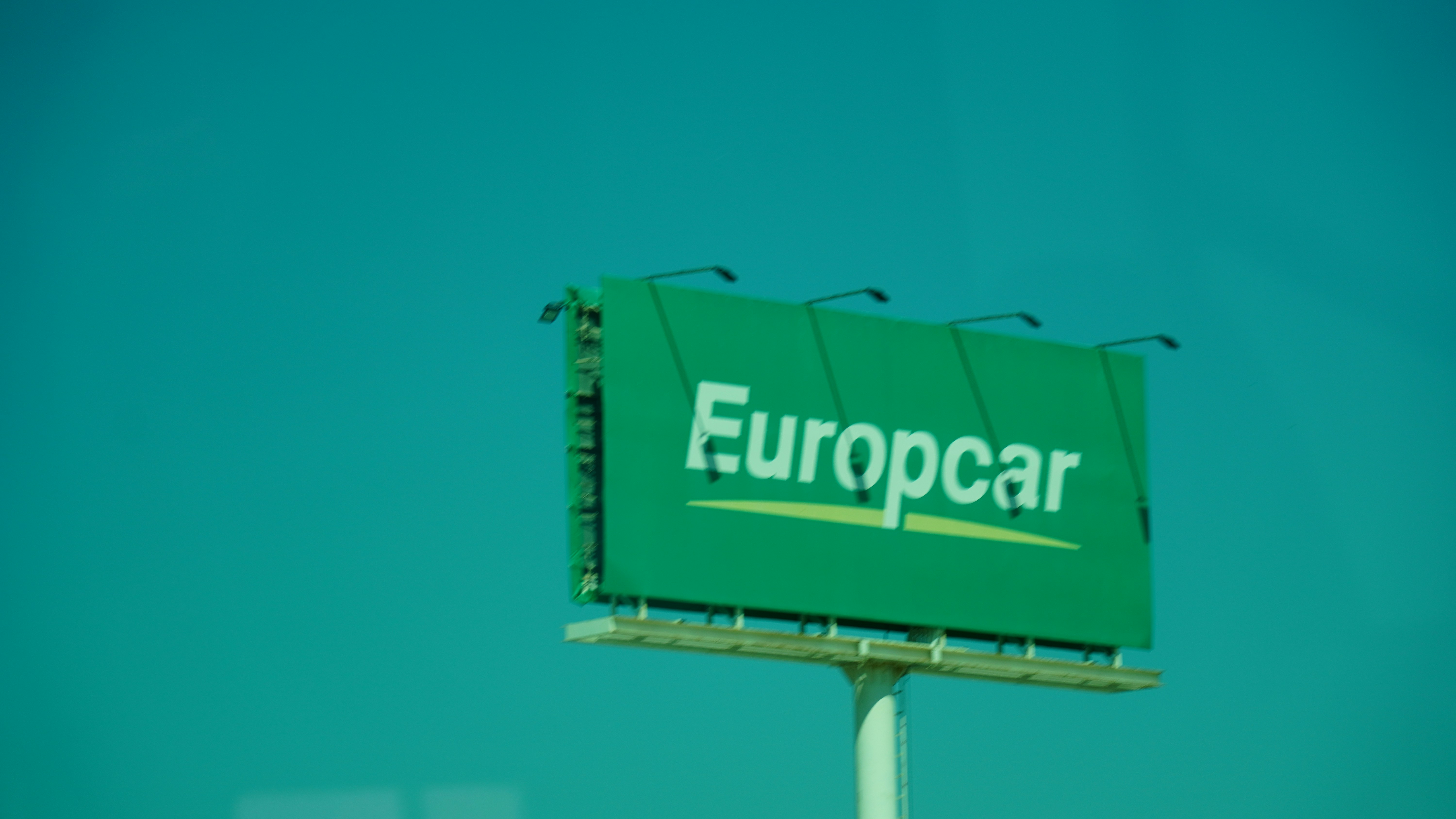 Green Europcar Billboard Soaring Above a Quiet Pole