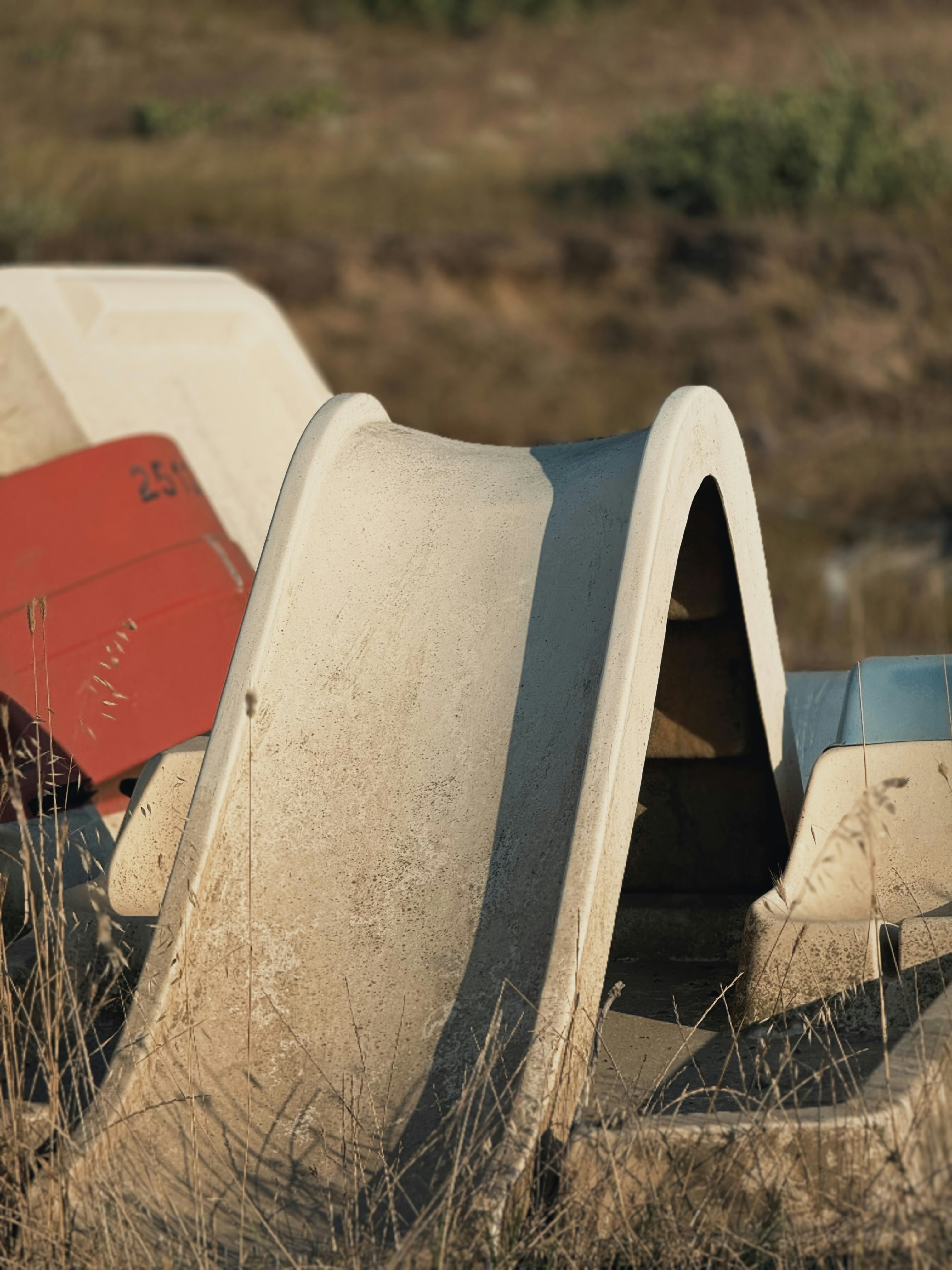 Deserted playground: weathered slides amid dry grasses