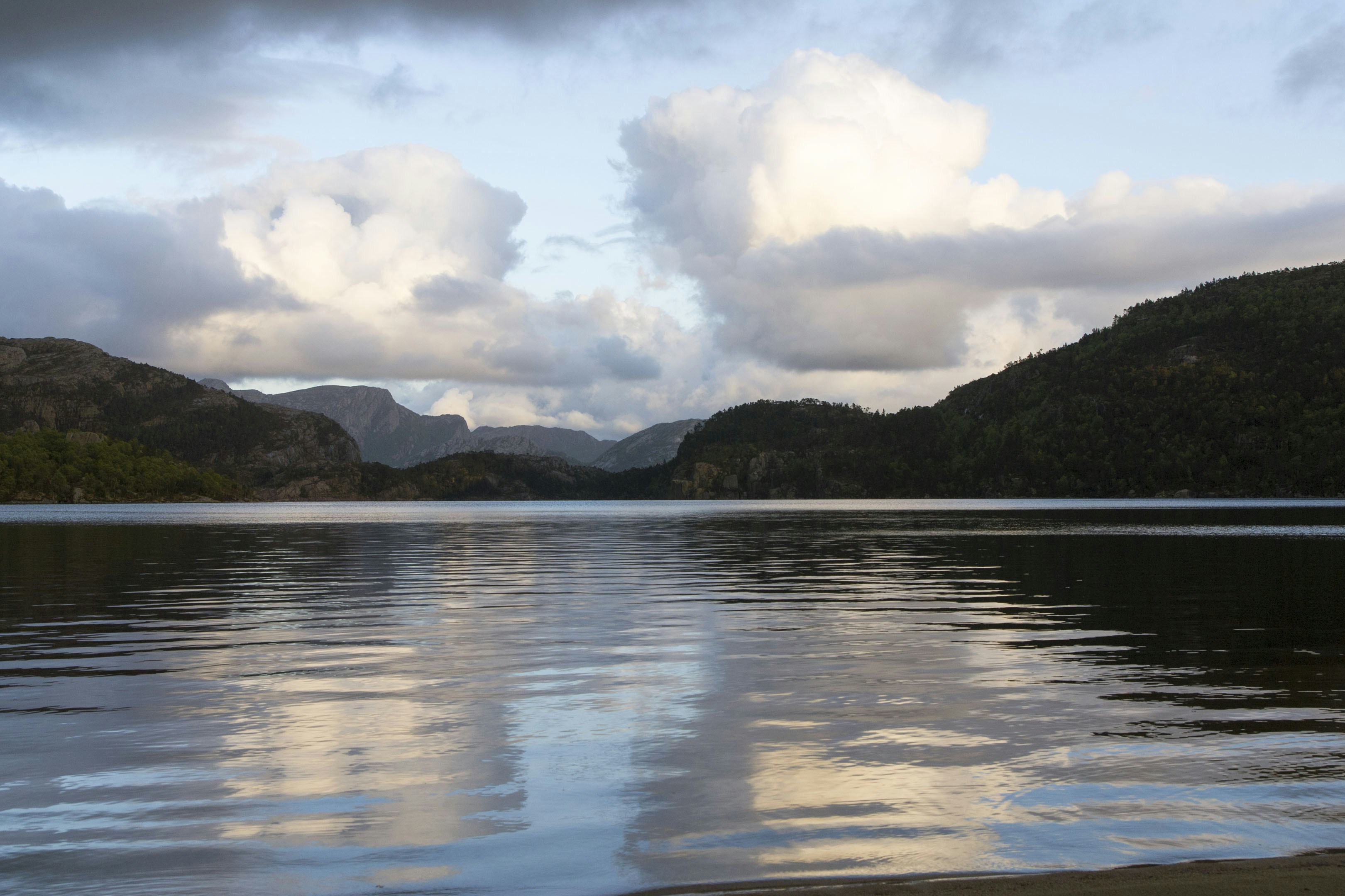 Quiet Fjord Mirror: Clouds and Hills Echo on Calm Waters