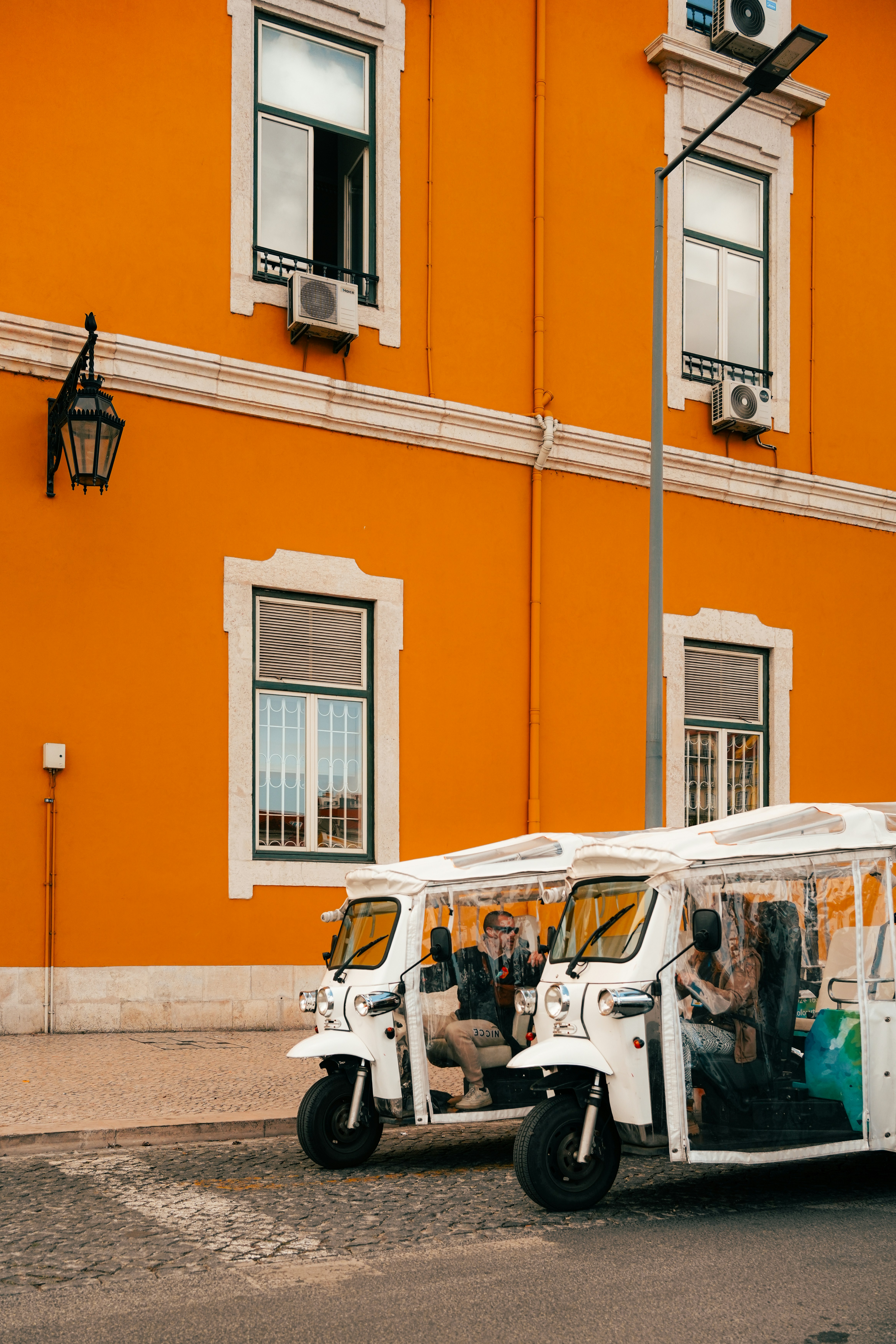 Sunlit Orange Facade with a Fleet of Covered Tuk-Tuks