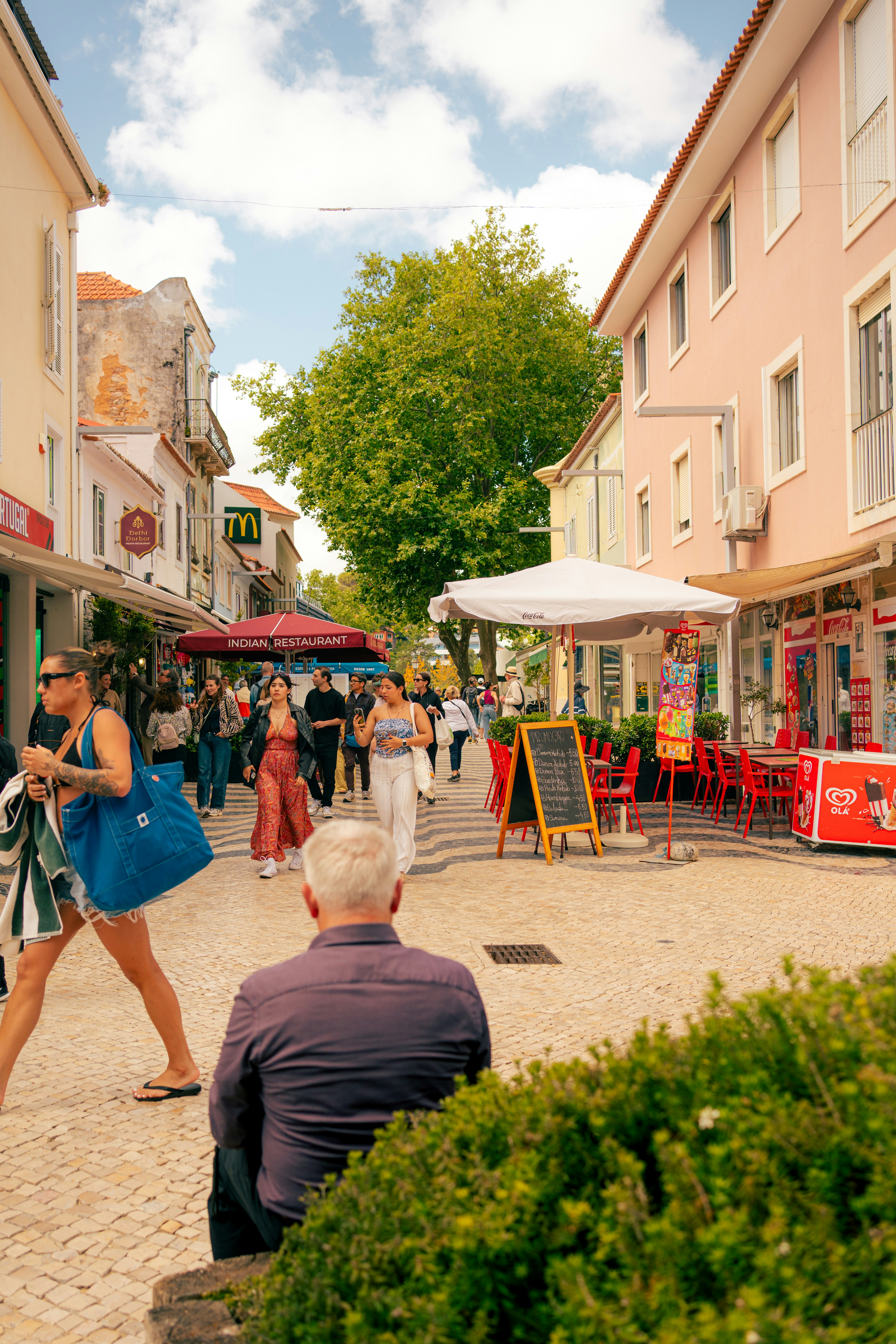Cobbled Street Pulse: Social Scene Under a Canopy of Trees