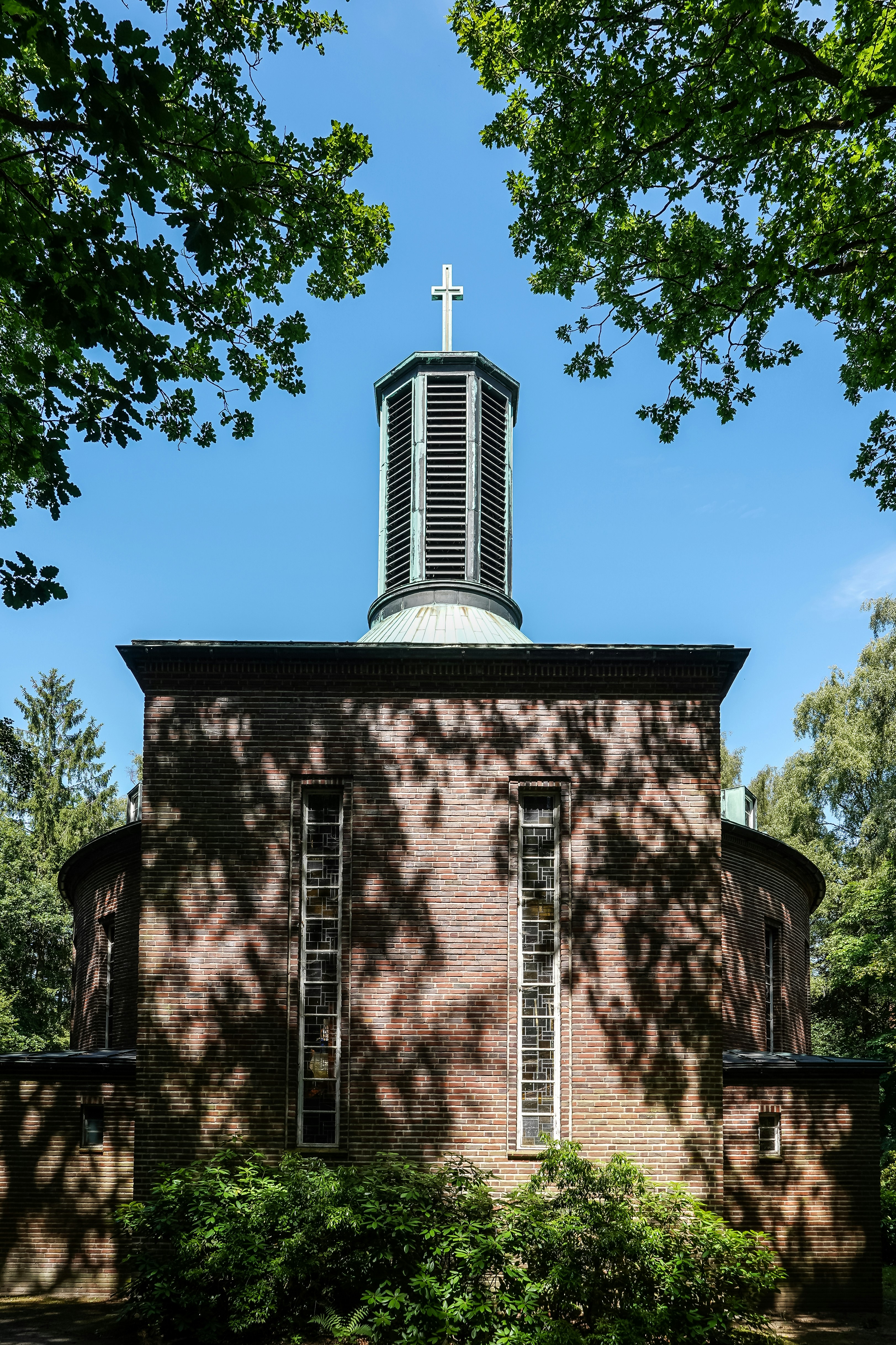 Sunlit Brick Chapel with Towered Steeple and Dappled Foliage