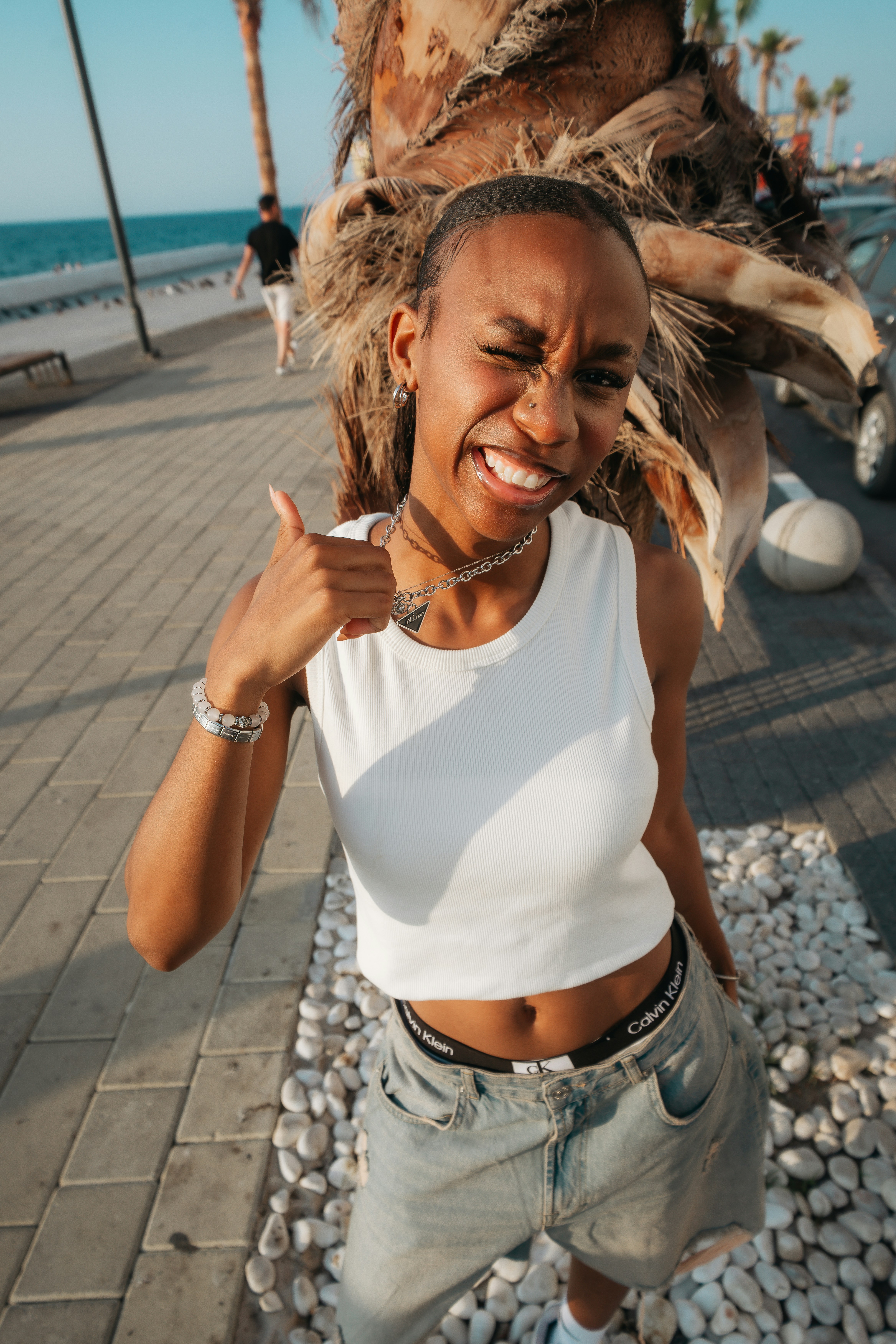 Thumbs Up Under Palm: Sunlit Confidence on the Boardwalk