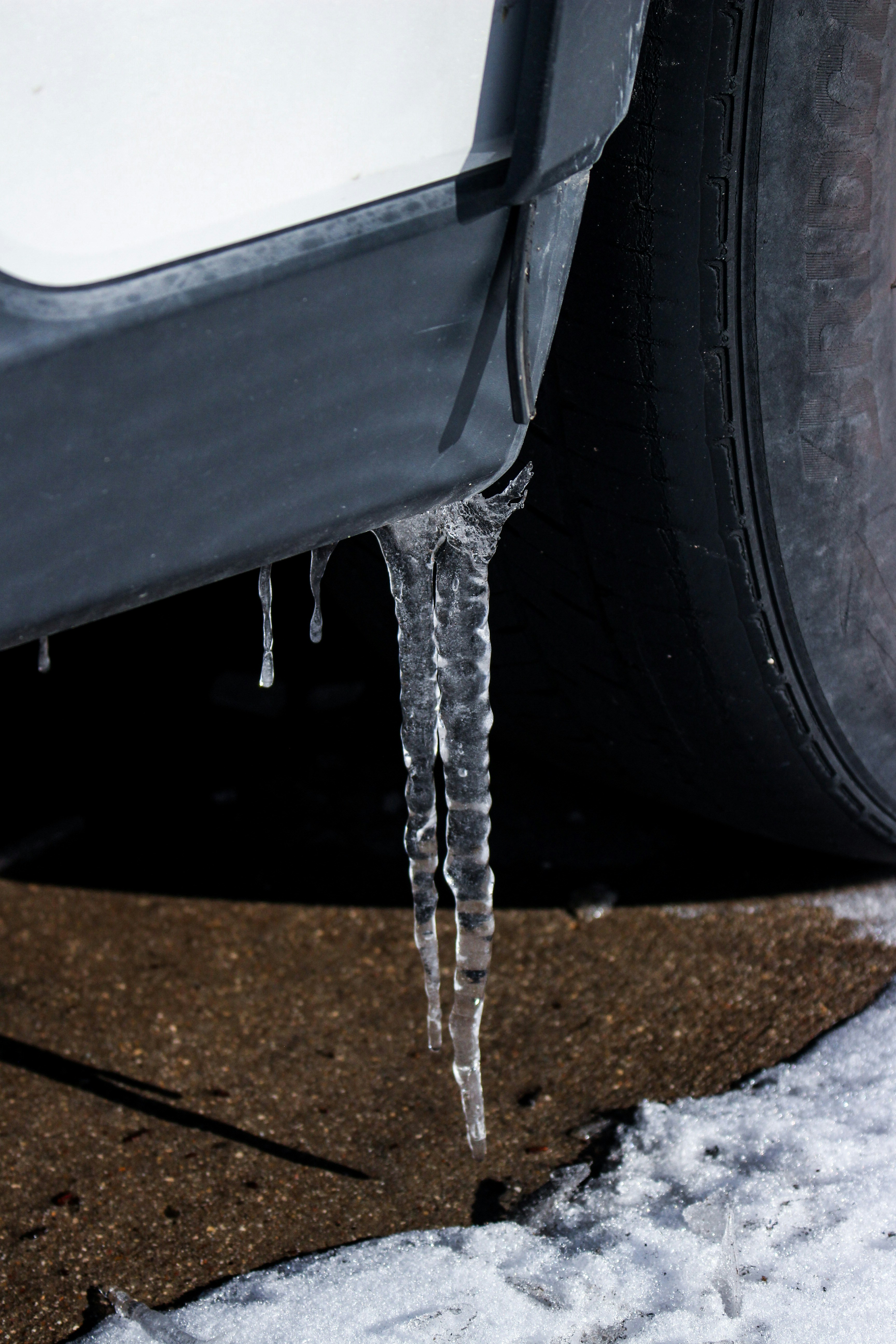 Icicle Pendant Under the Car: Cold Light on a Winter Rim