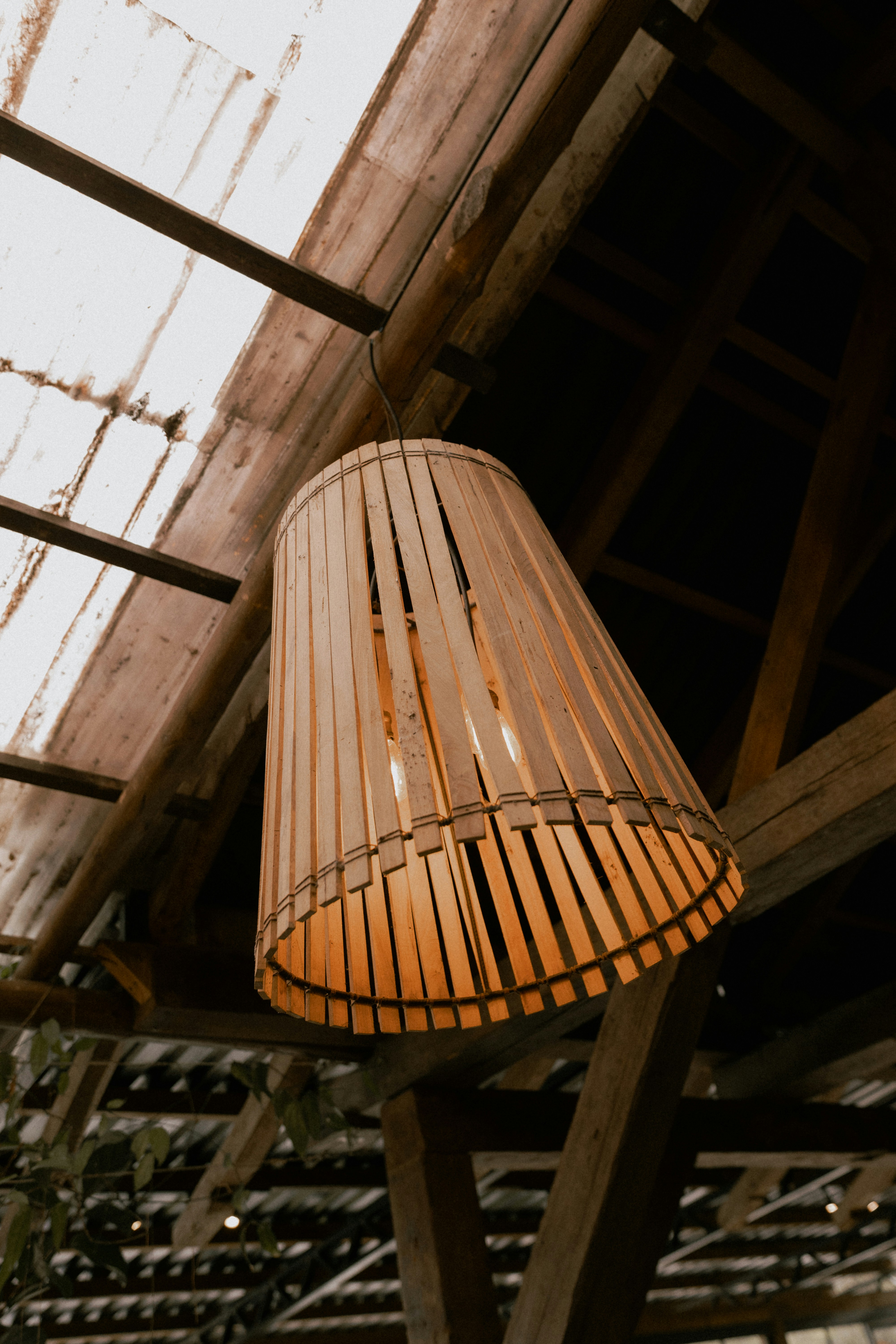 A wooden slatted lamp hangs from a rustic ceiling structure.