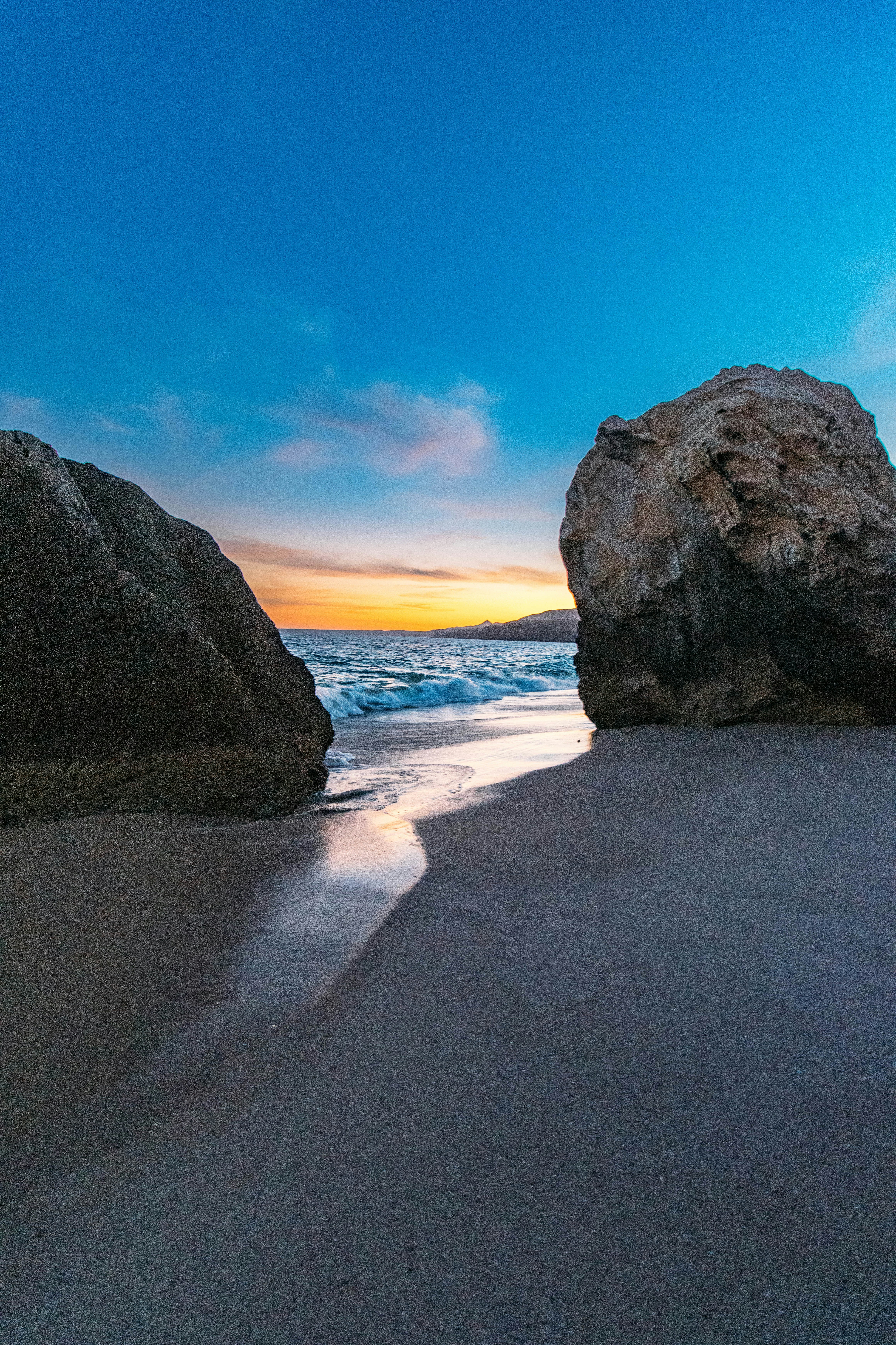 Sunset Between Giants: A Quiet Beach Between Weathered Rocks