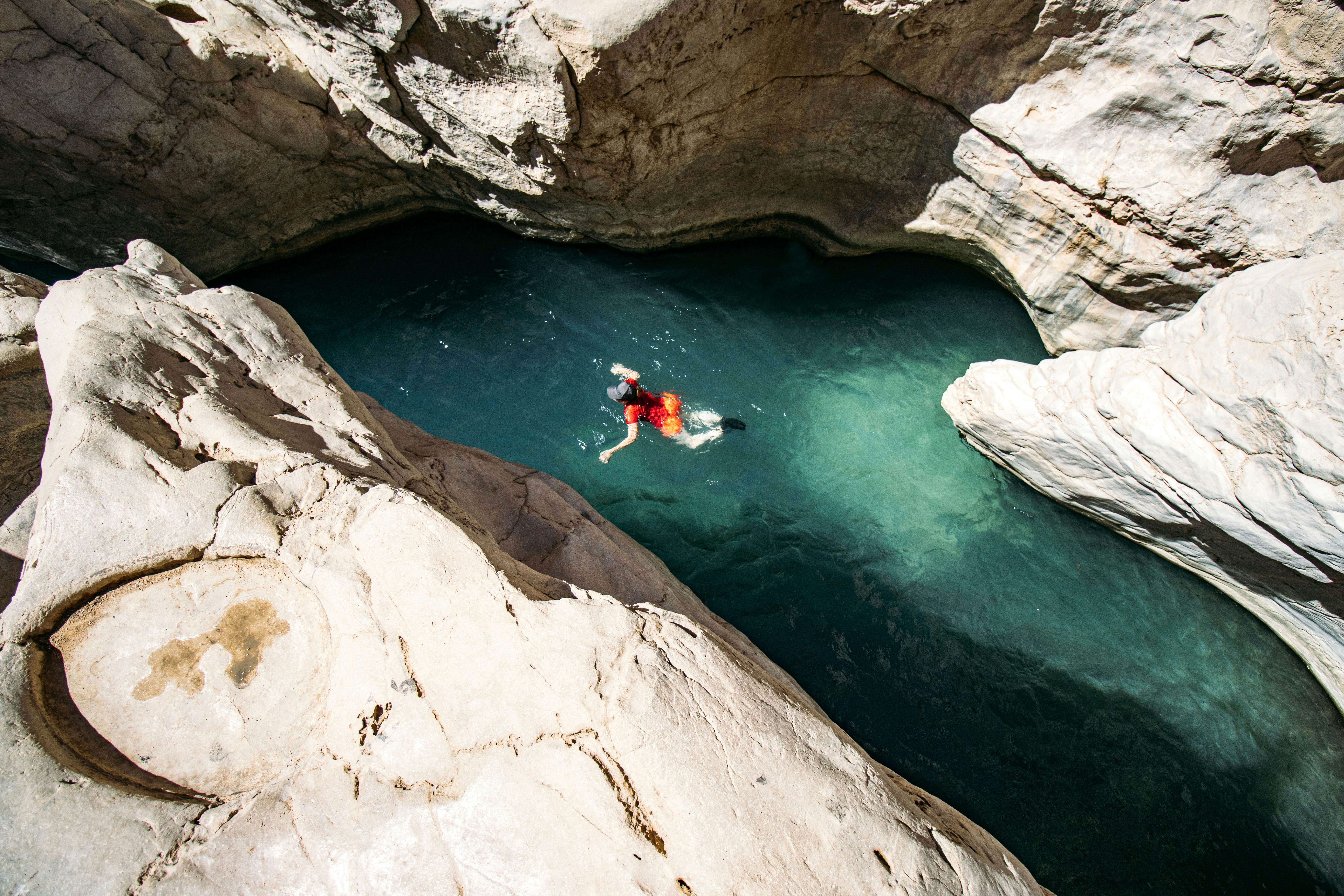 Emerald Gorge Dive: A Swimmer Amid White Canyon Walls