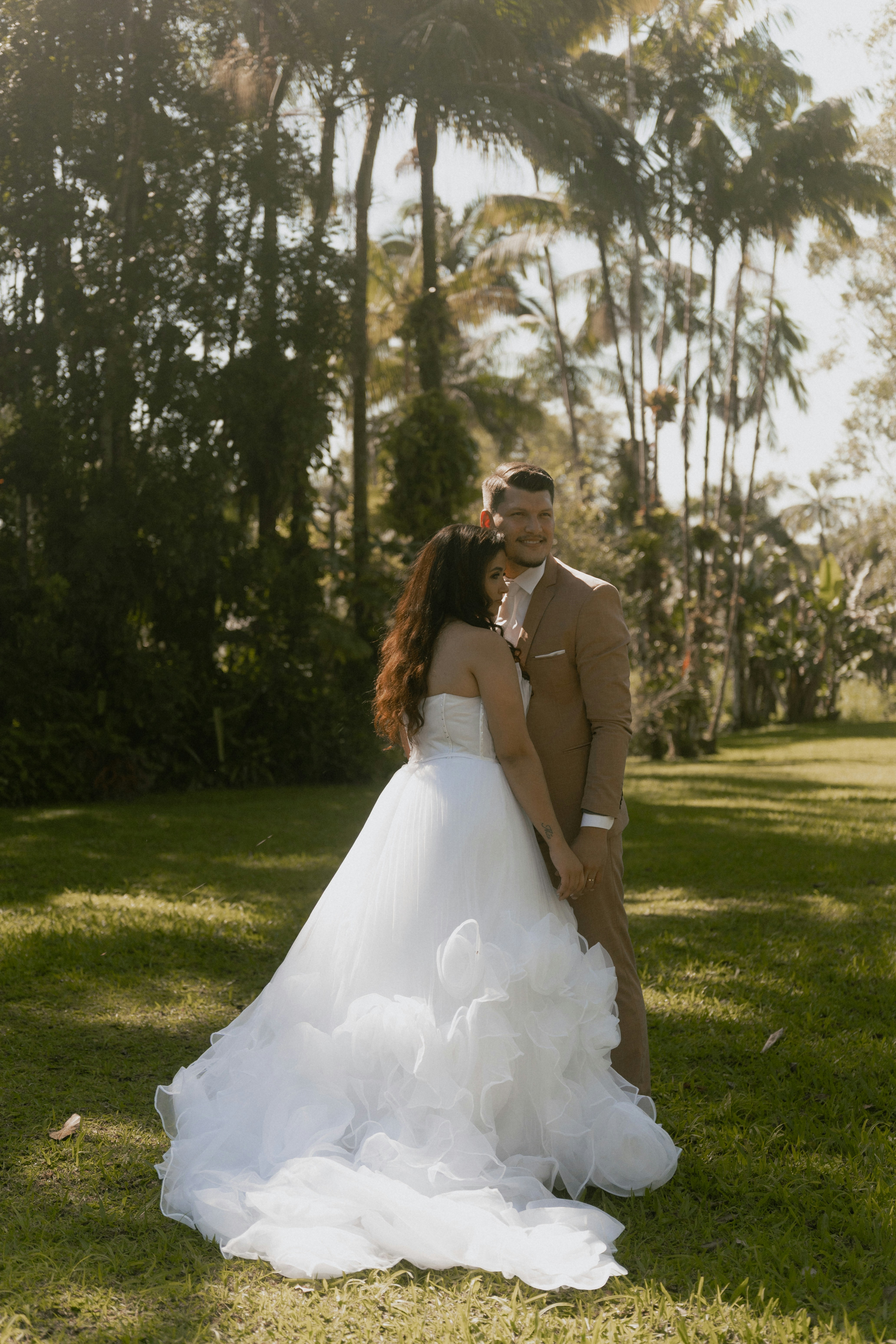 Bride and groom in golden-hour embrace beneath tropical palms