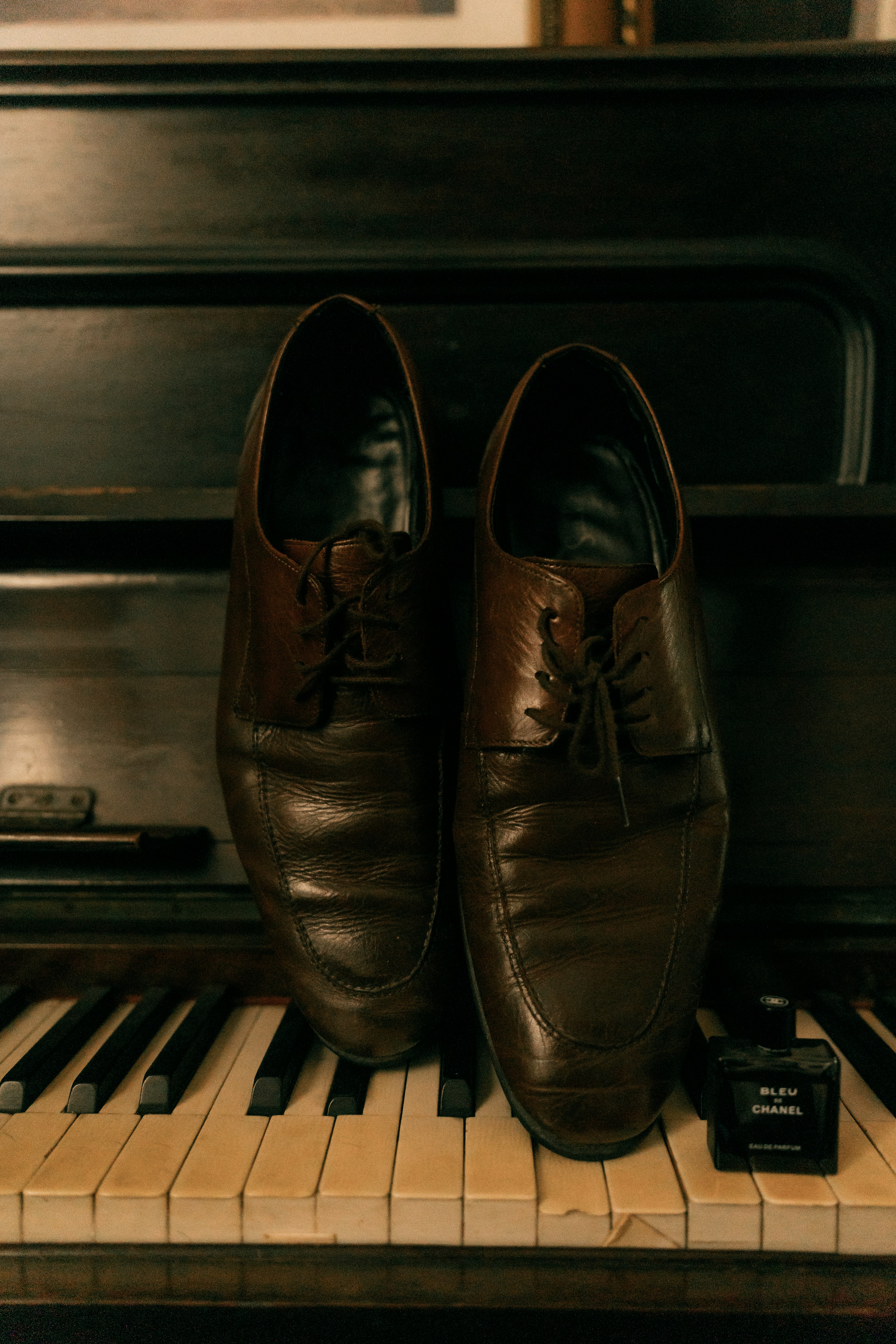 Brown Leather Shoes Resting on a Vintage Piano Keyboard