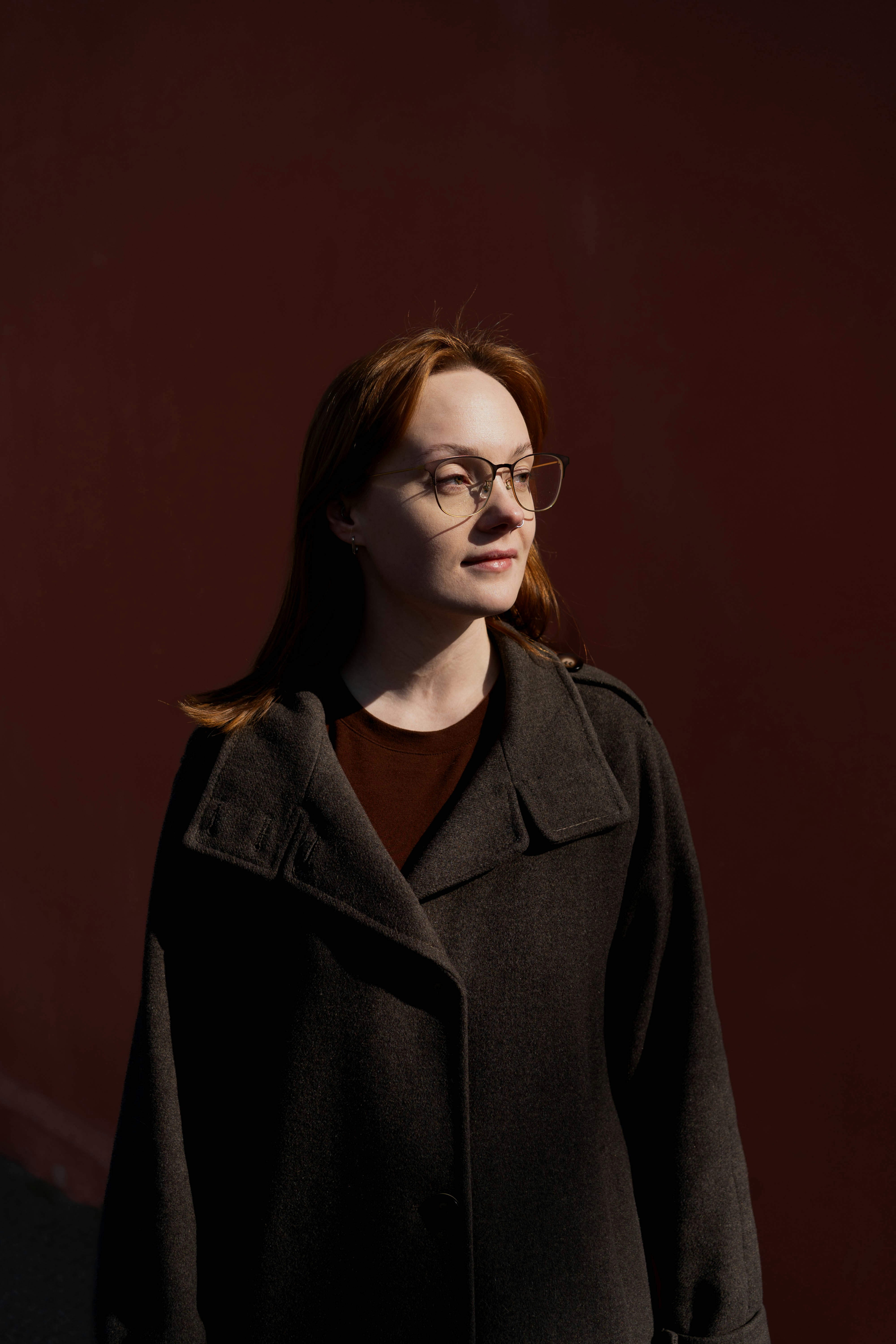 Slim silhouette in warm light: a portrait against a brick-toned backdrop