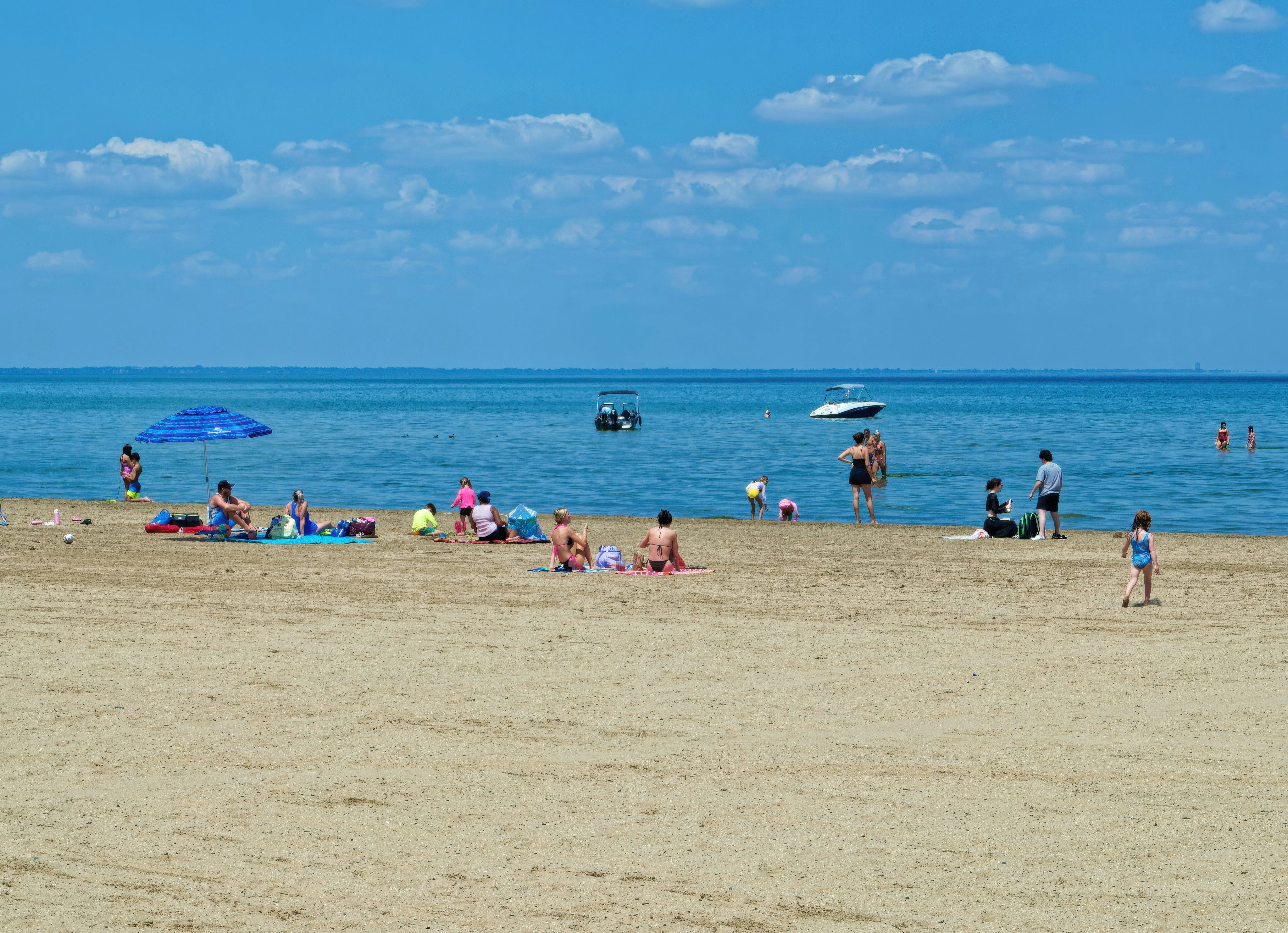 Sunlit Beach Mosaic: Families and Boats at Distant Blue