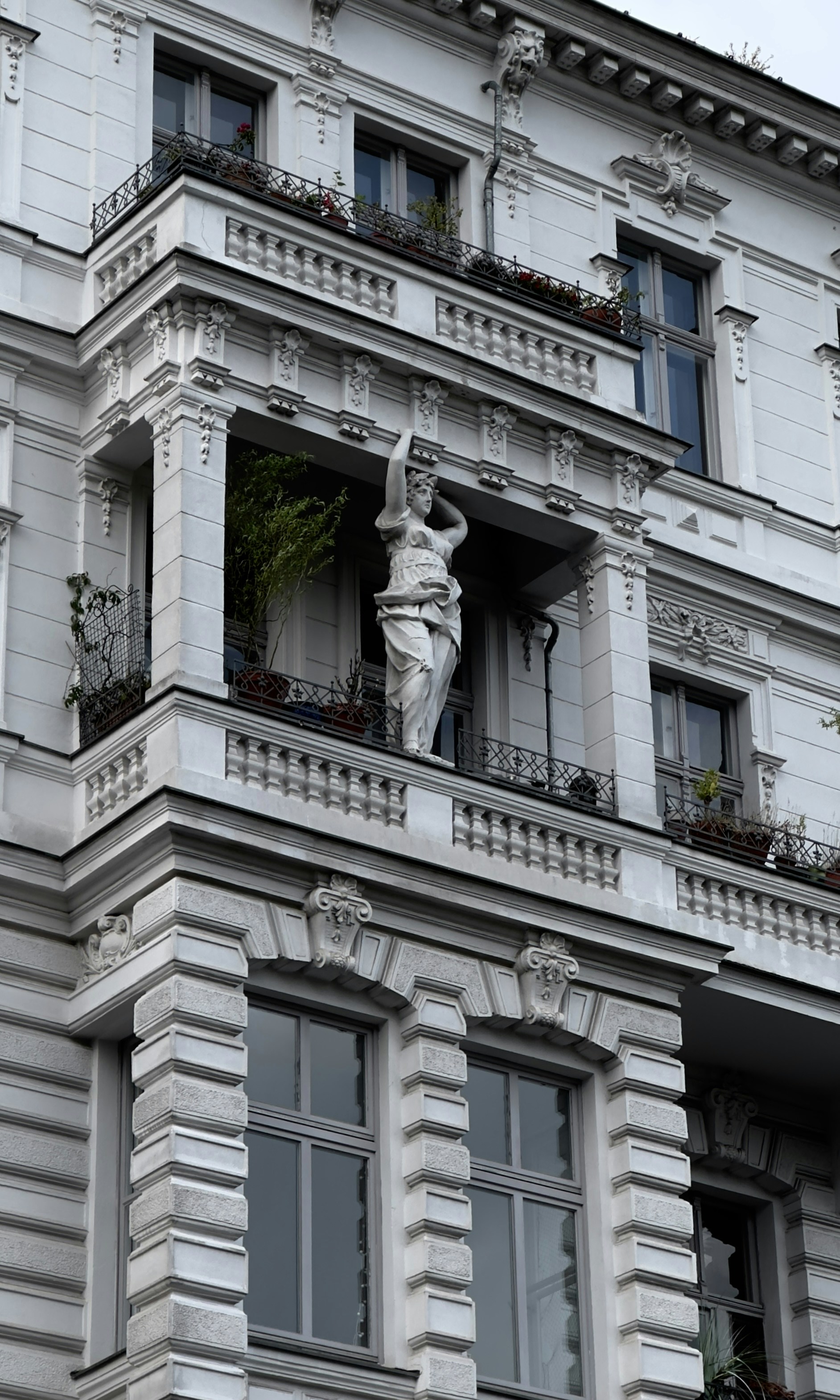 Statue on a Historic Facade: A Sculpted Sentinel Above Ornate Windows