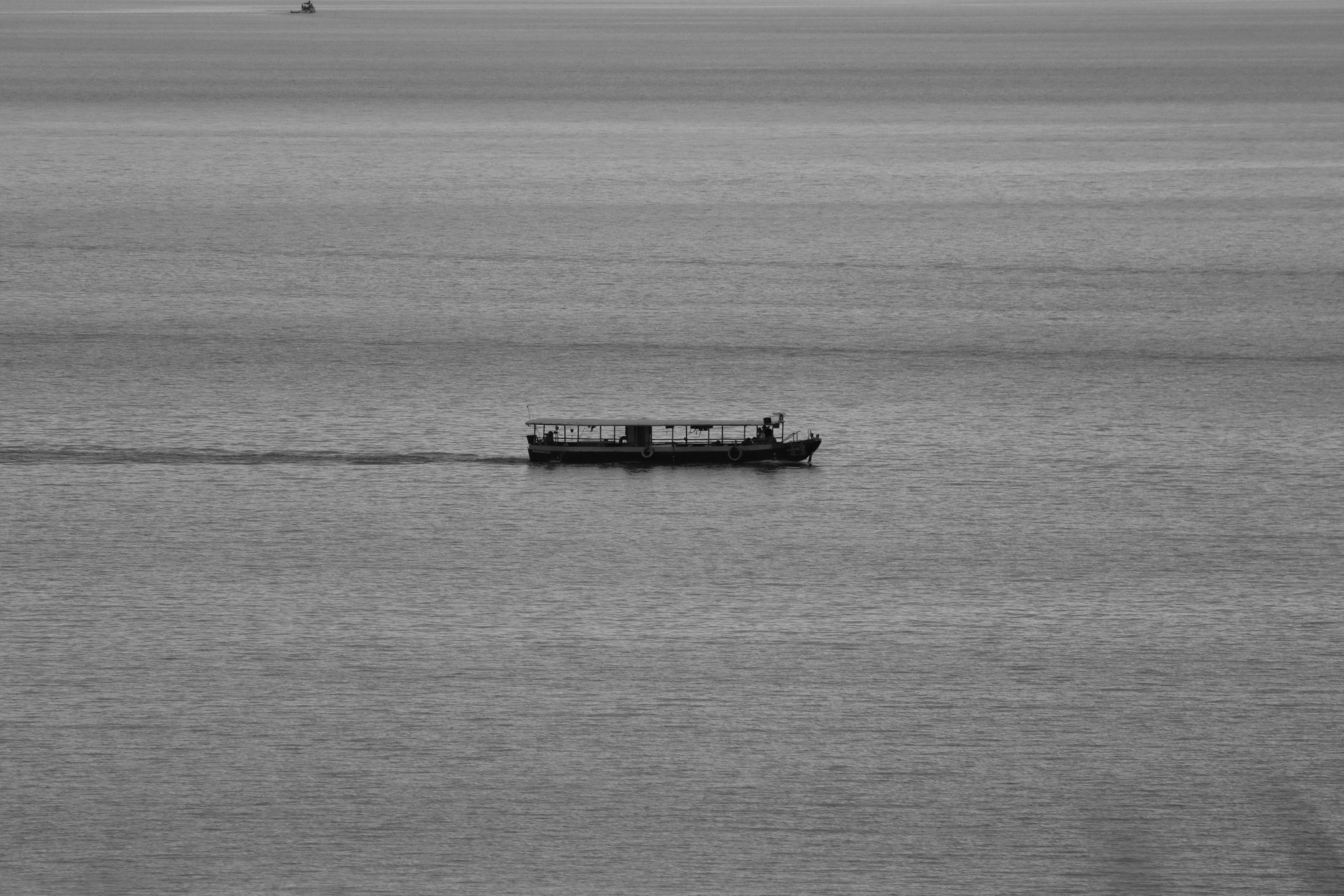 Silhouette over Silver Seas: A lone boat across calm horizons