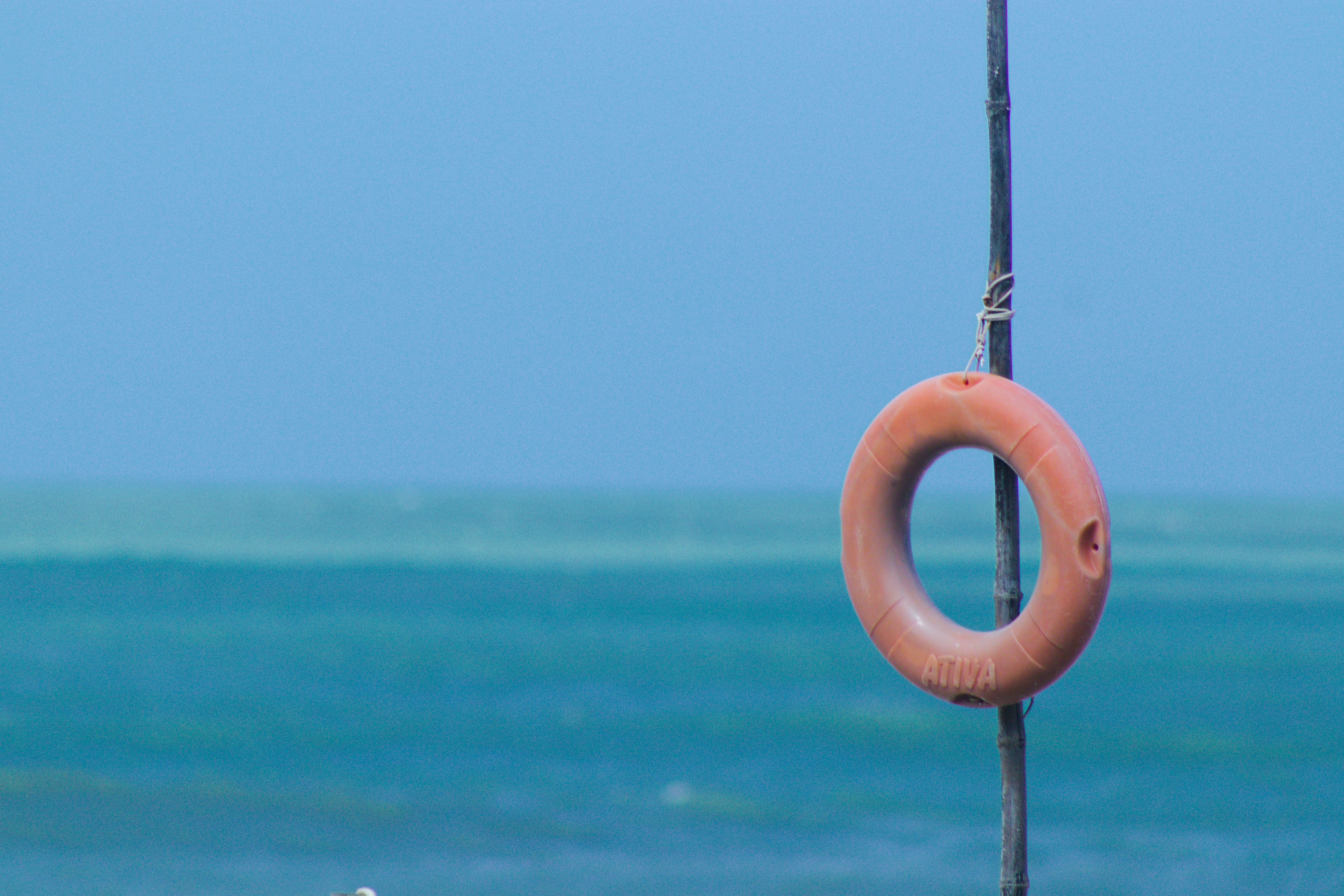 Lifebuoy on a Weathered Rope Against Teal Sea