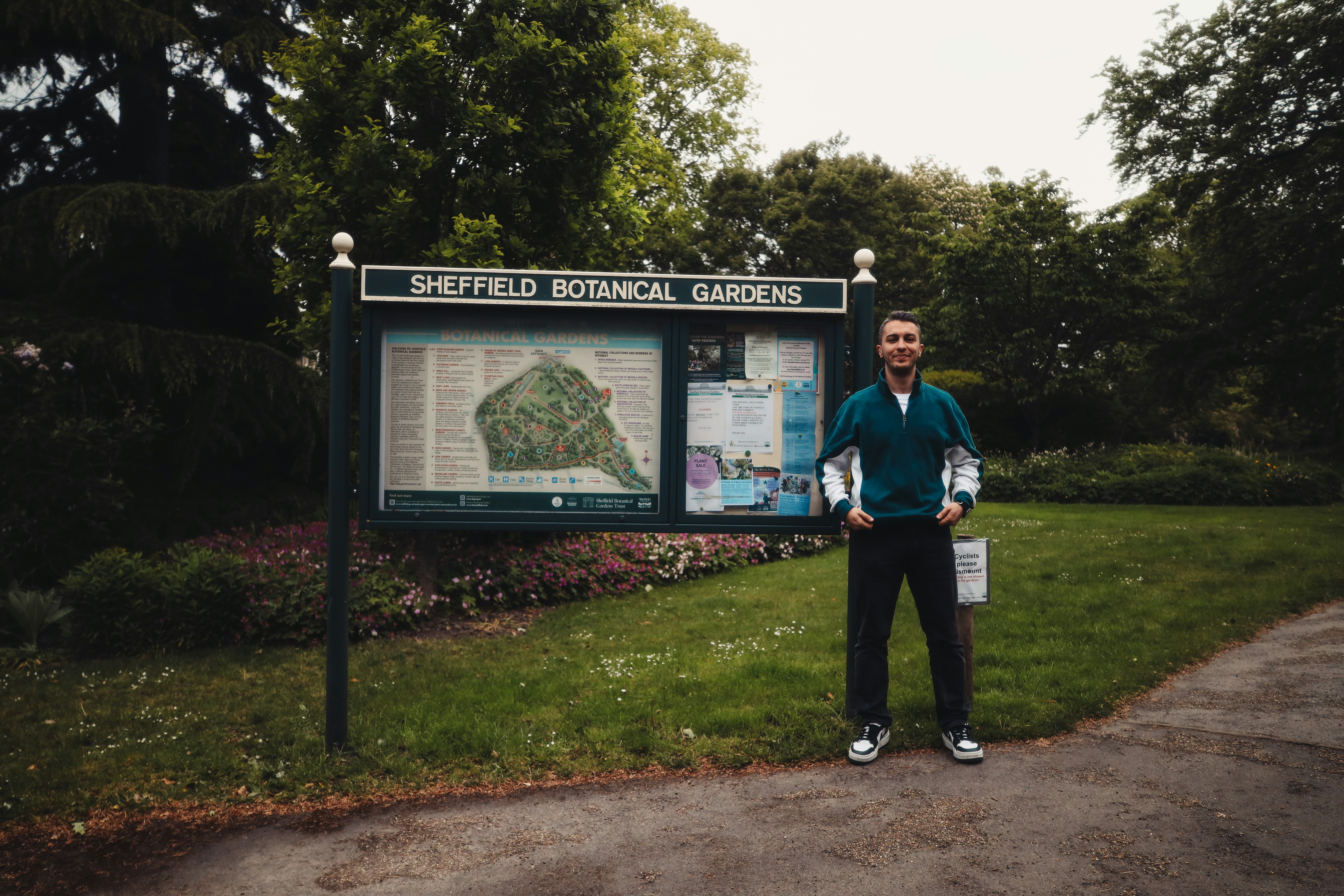 Guide at the Gates: A Man Stands by the Botanical Noticeboard