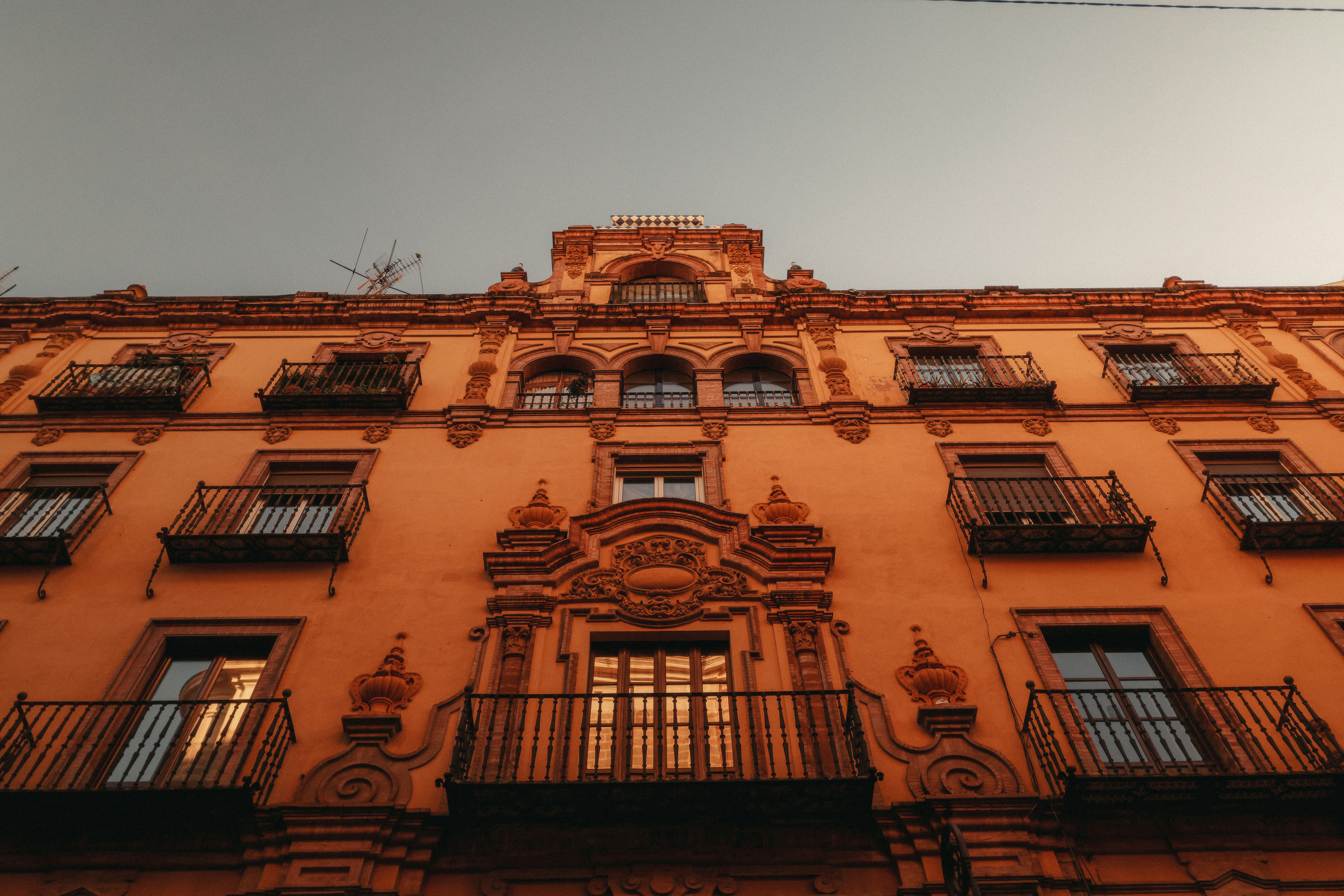 Ornate Facade Under Soft Dusk: A Tall Orange Building with Balcony Details