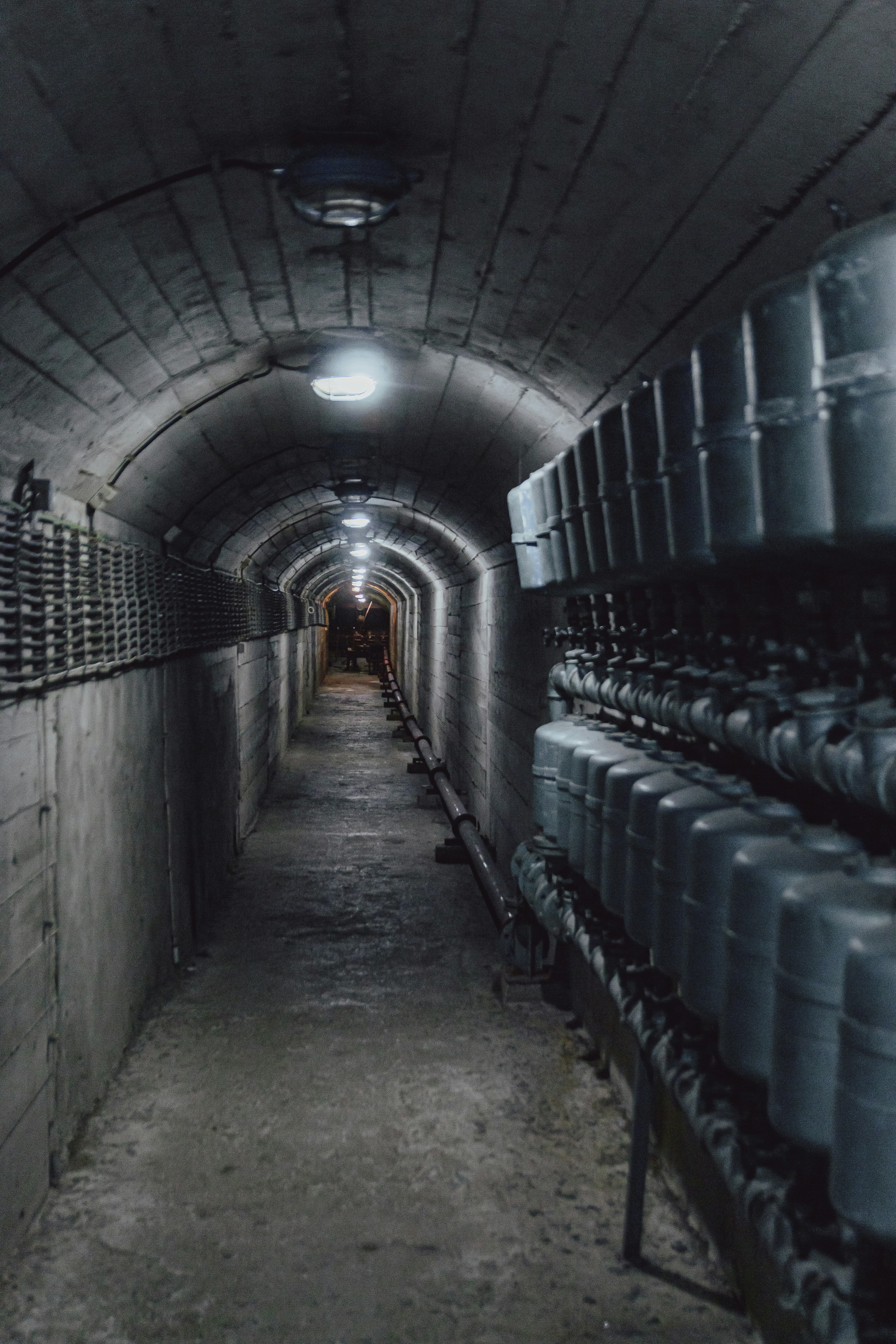 Hidden deep within the mountains of Konjic, Tito’s bunker stands as a monumental relic of Cold War secrecy. The photographs capture its vast concrete corridors, heavy steel doors, and silent chambers—spaces once designed to protect a nation’s leadership from nuclear threat. Today, the emptiness resonates with echoes of history, transforming the bunker into a stage where power, fear, and memory converge. Light filtering through narrow openings softens the stark architecture, turning this underground fortress into a haunting dialogue between past and present.