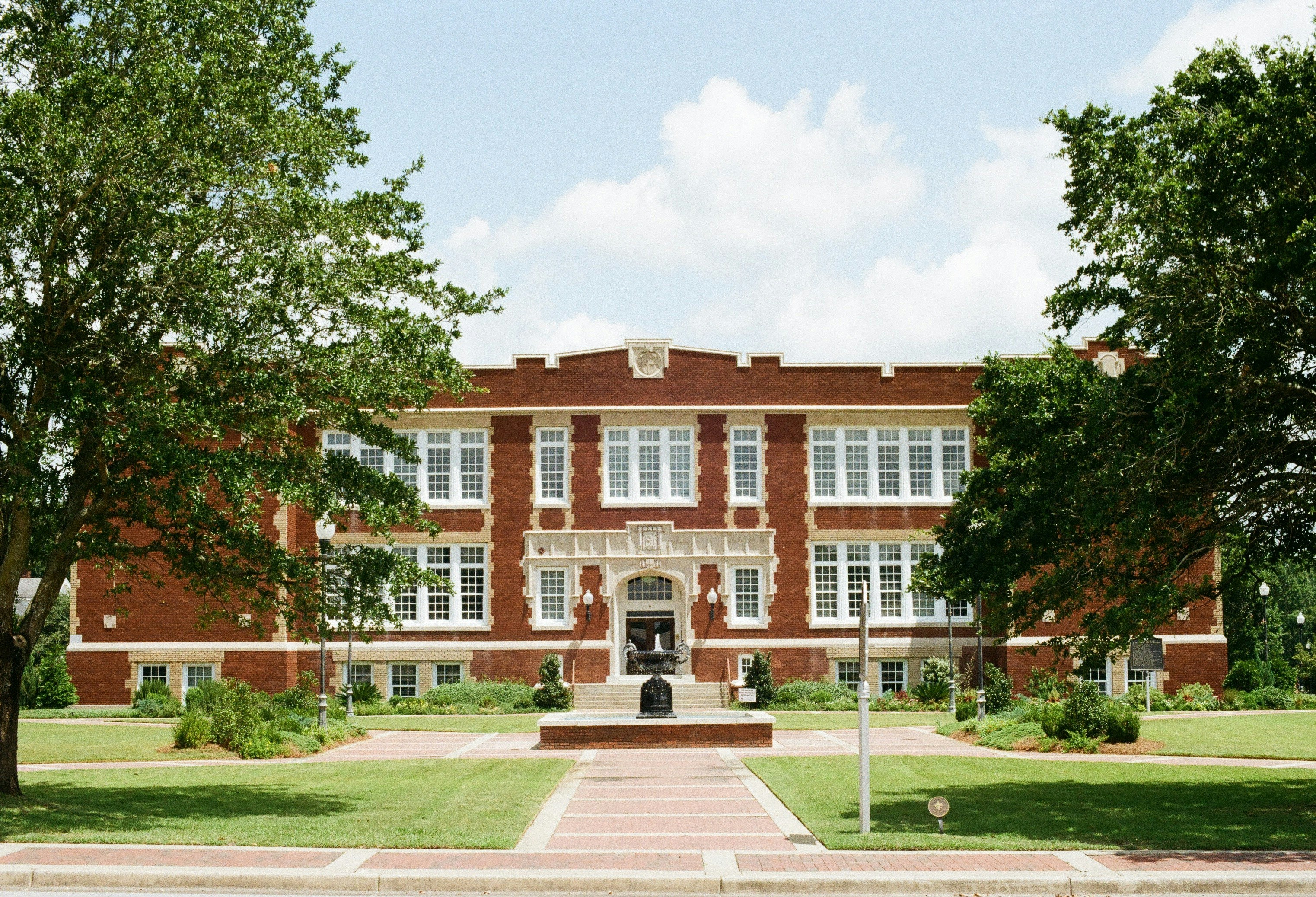 Symmetrical Brick Campus Facade Framed by Green Canopies