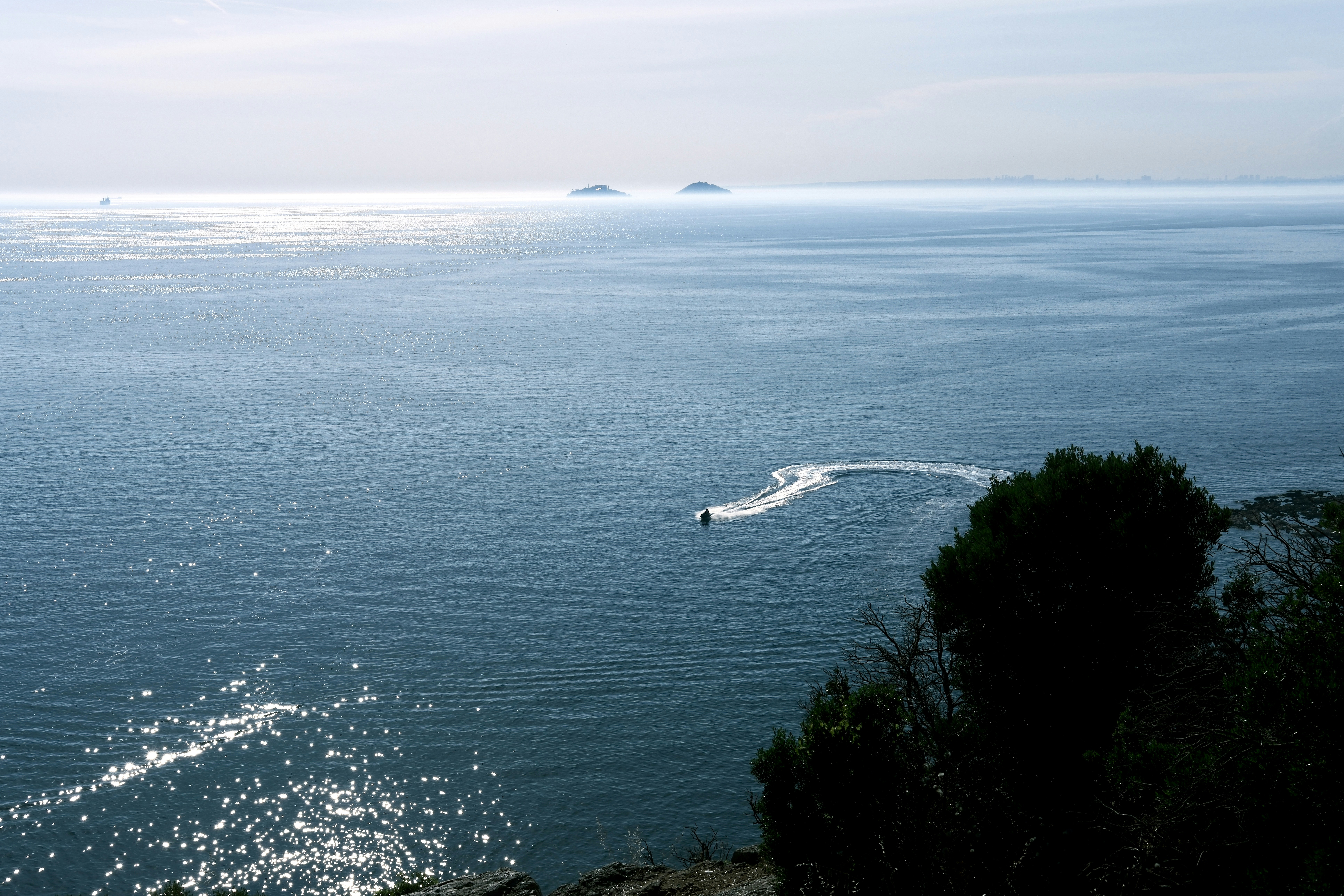 Blue Horizon: A Boat Traces a Silver Wake Across Quiet Seas