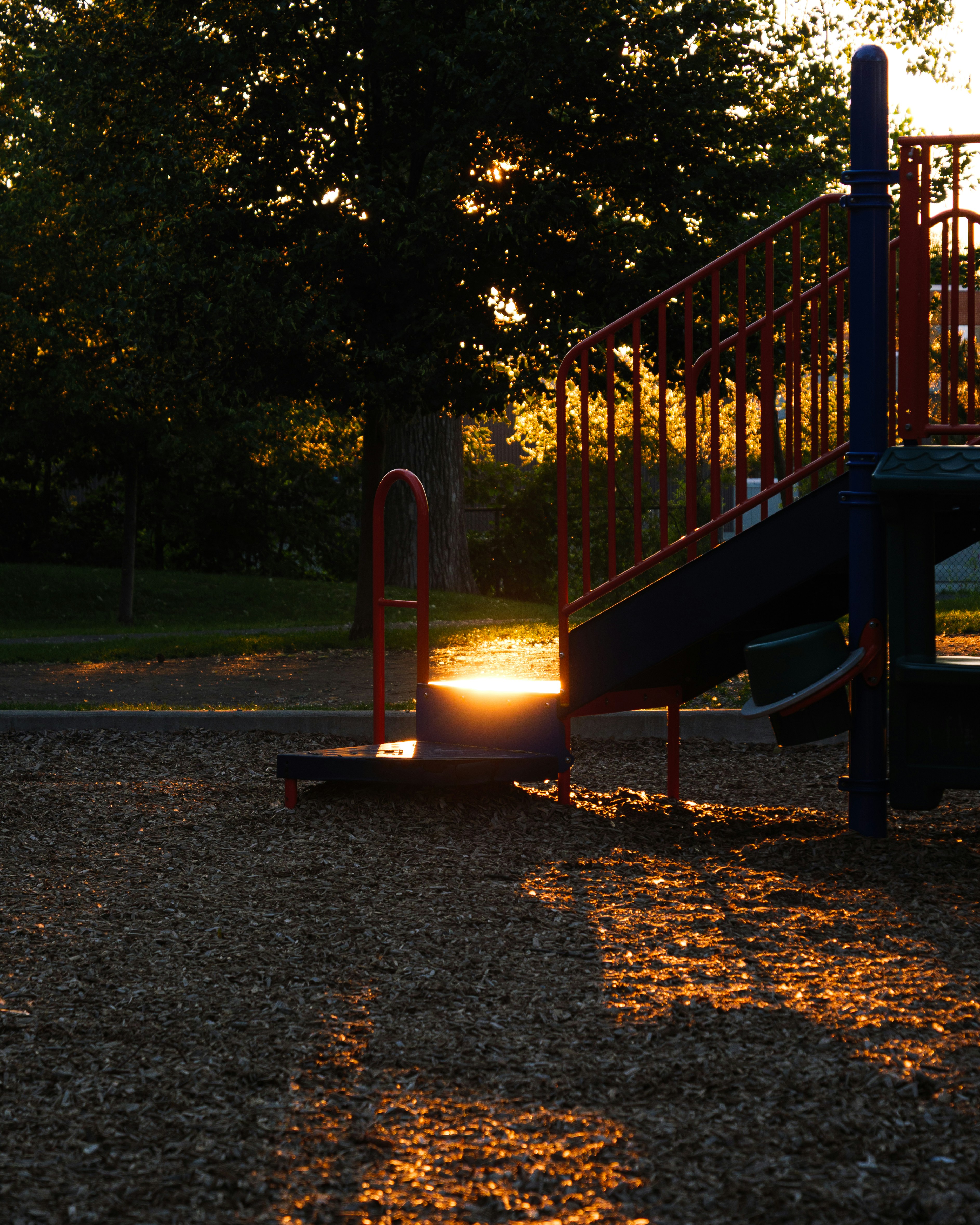 Sunlit Playground at Dusk: The Quiet Spotlight on a Shaded Slide