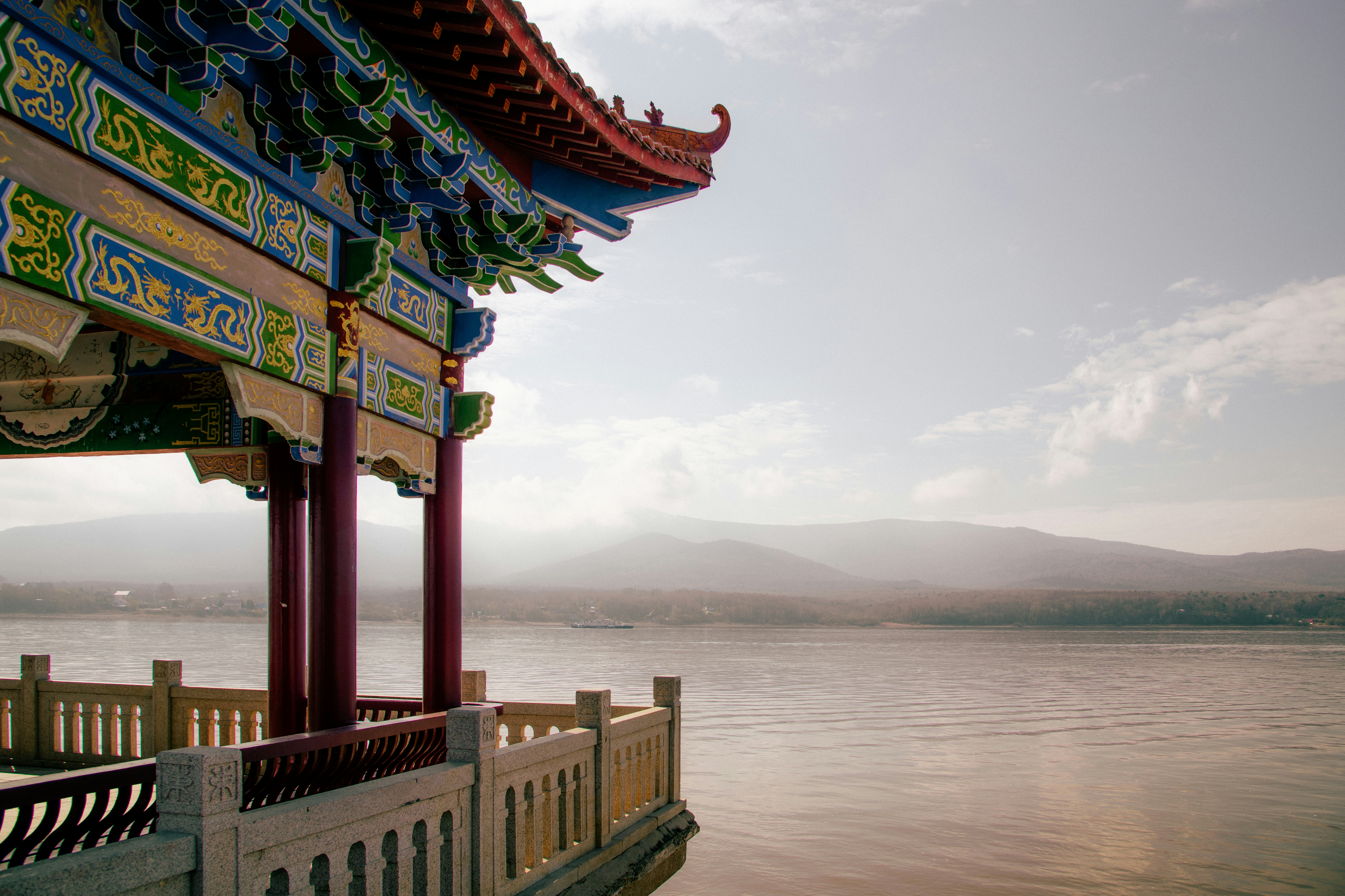 Stone railing and ornate pavilion framing a tranquil lakeside horizon