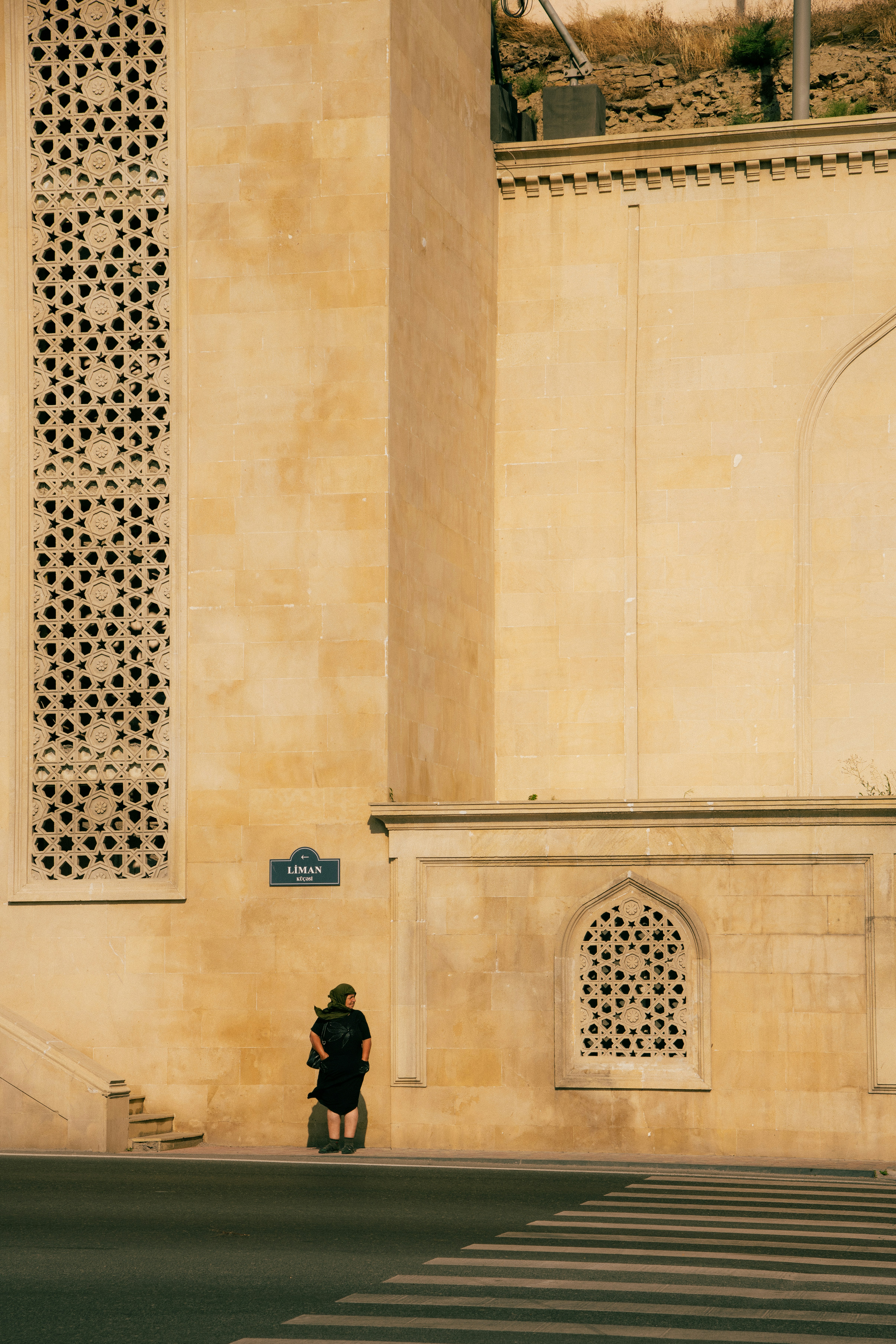 Shadowed figures at the base of a sunlit architectural Wall