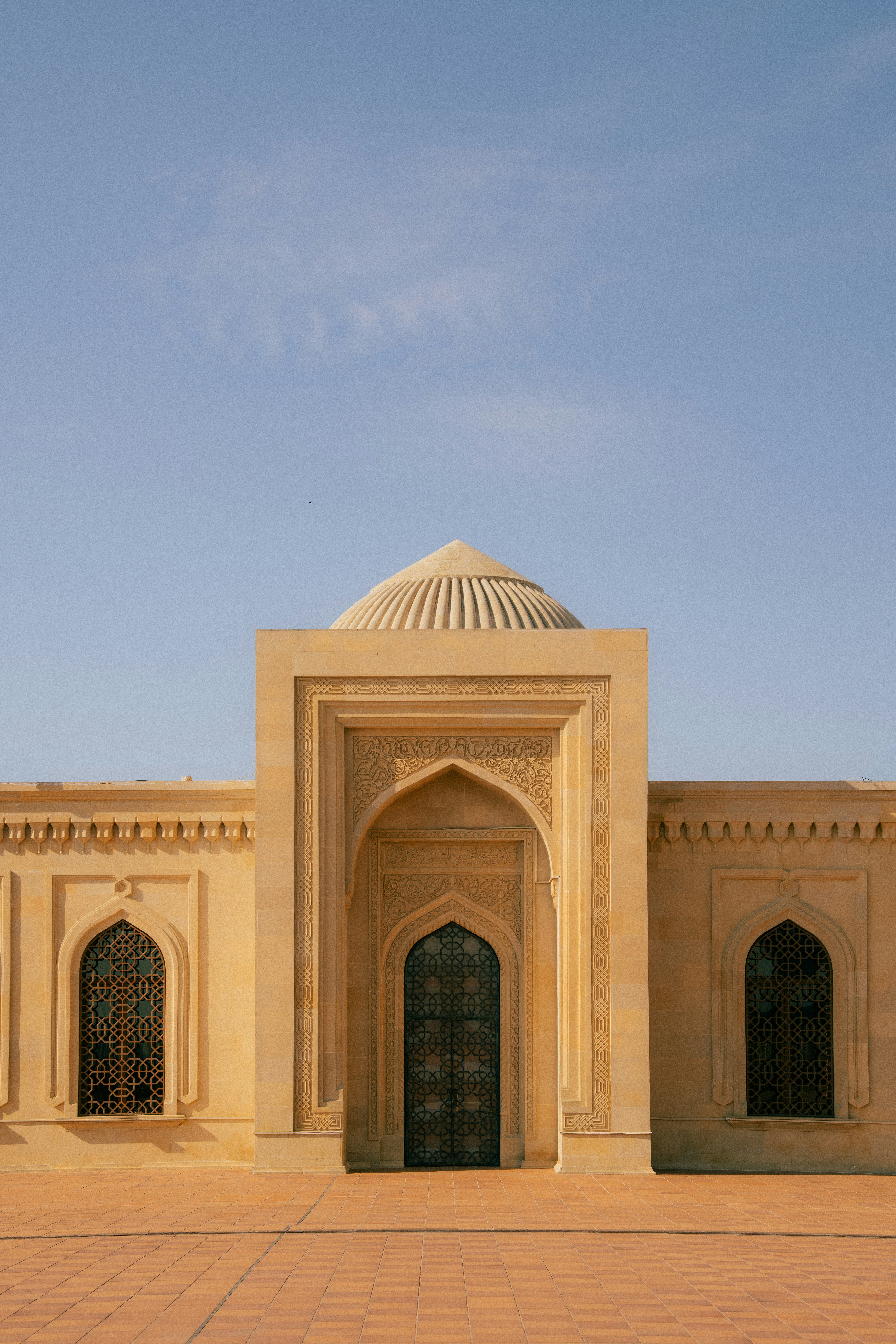 Gateway of Dunes: Carved Archways and Dome in Desert Facade
