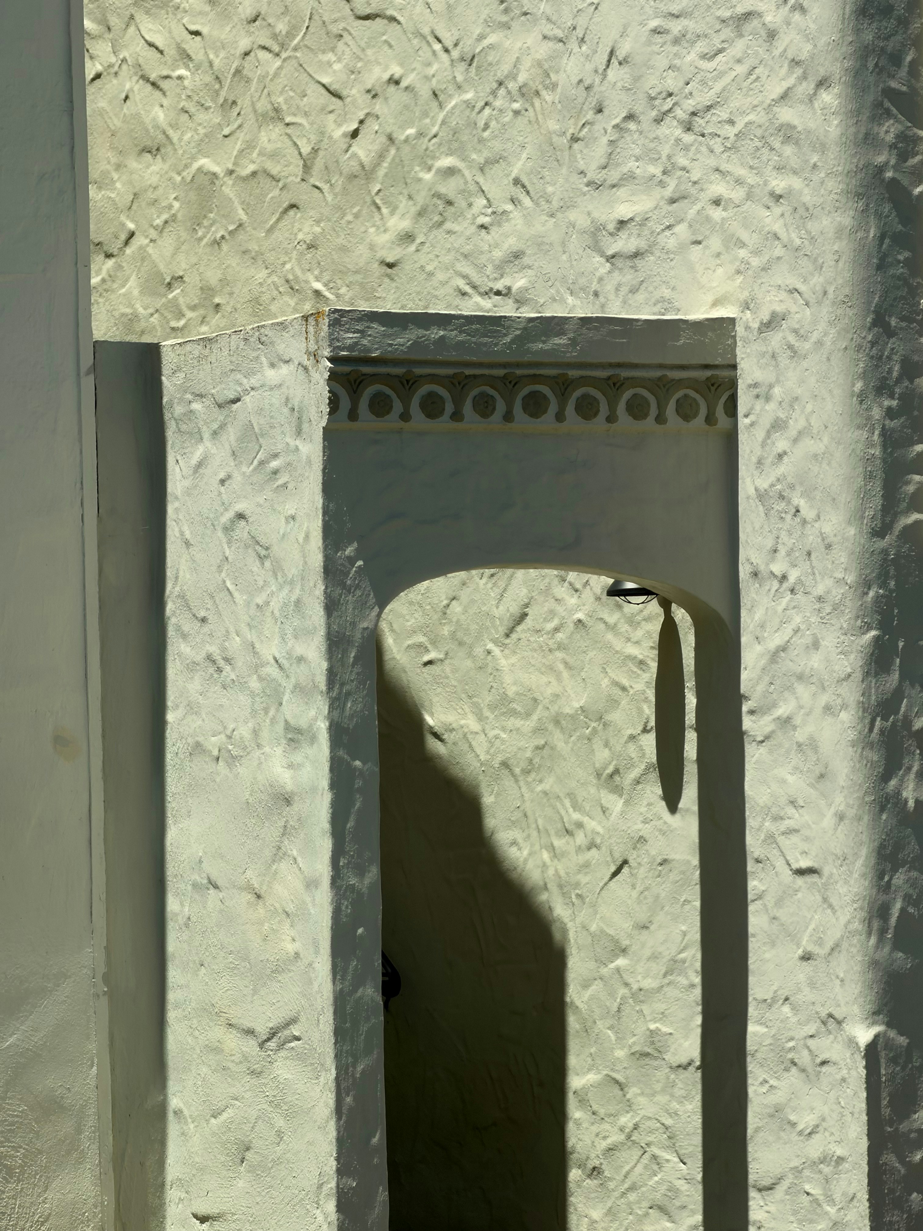 Sunlit Archway Shadow on a Textured Facade