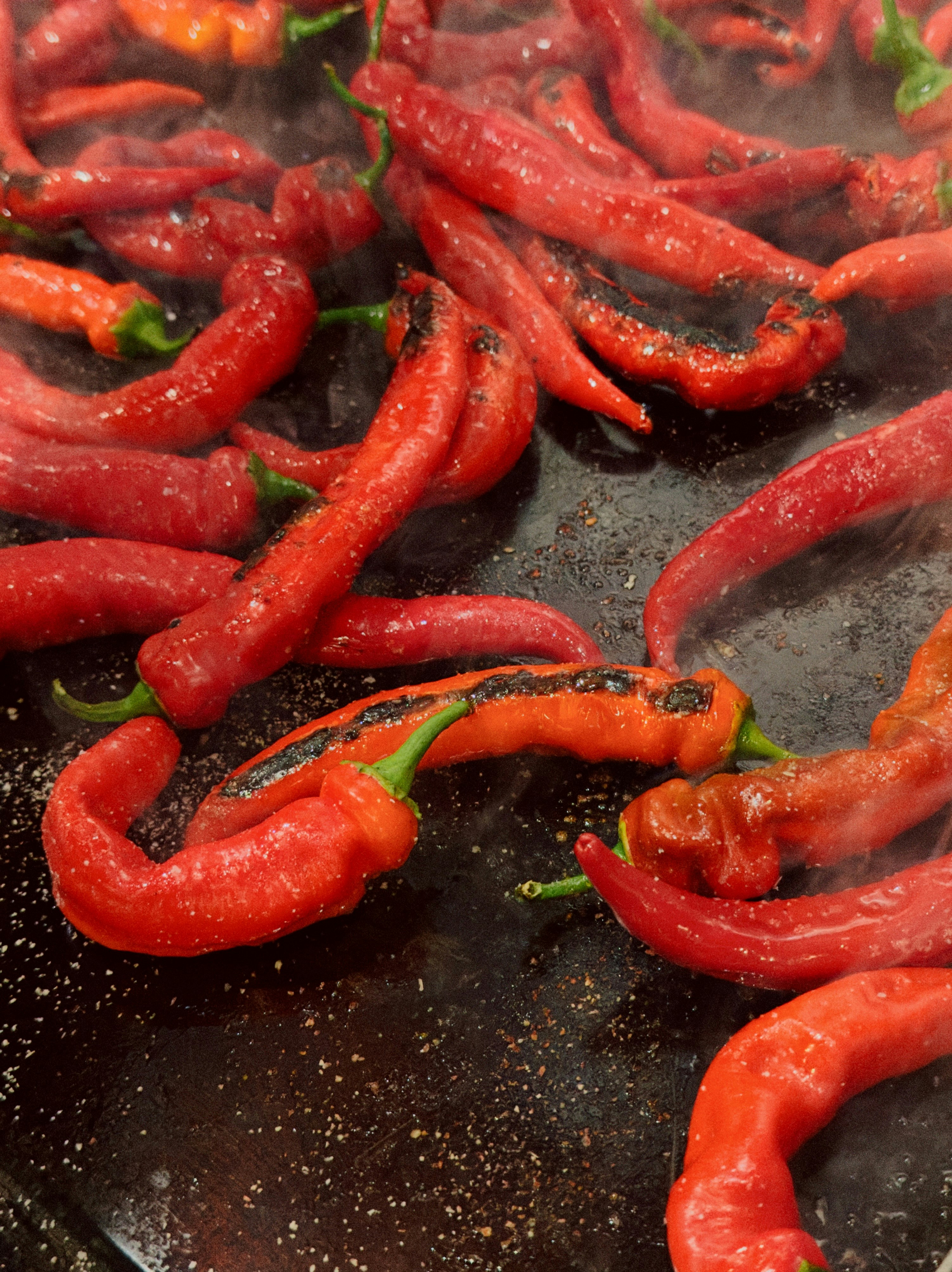 Red Pepper Inferno: Charred, Scattered Chili Peppers on a Hot Griddle