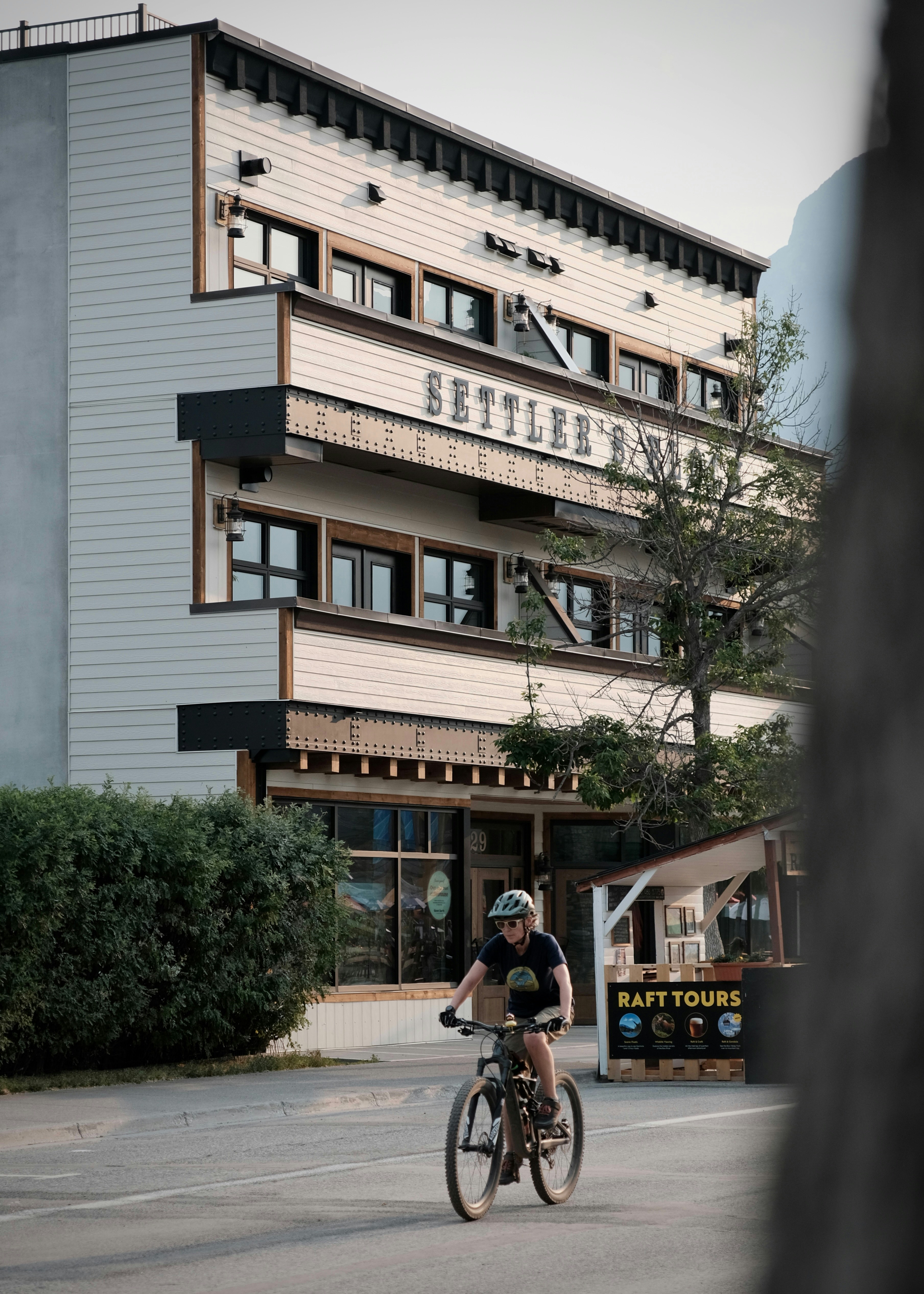 Cyclist under a layered hotel façade on a sunlit street