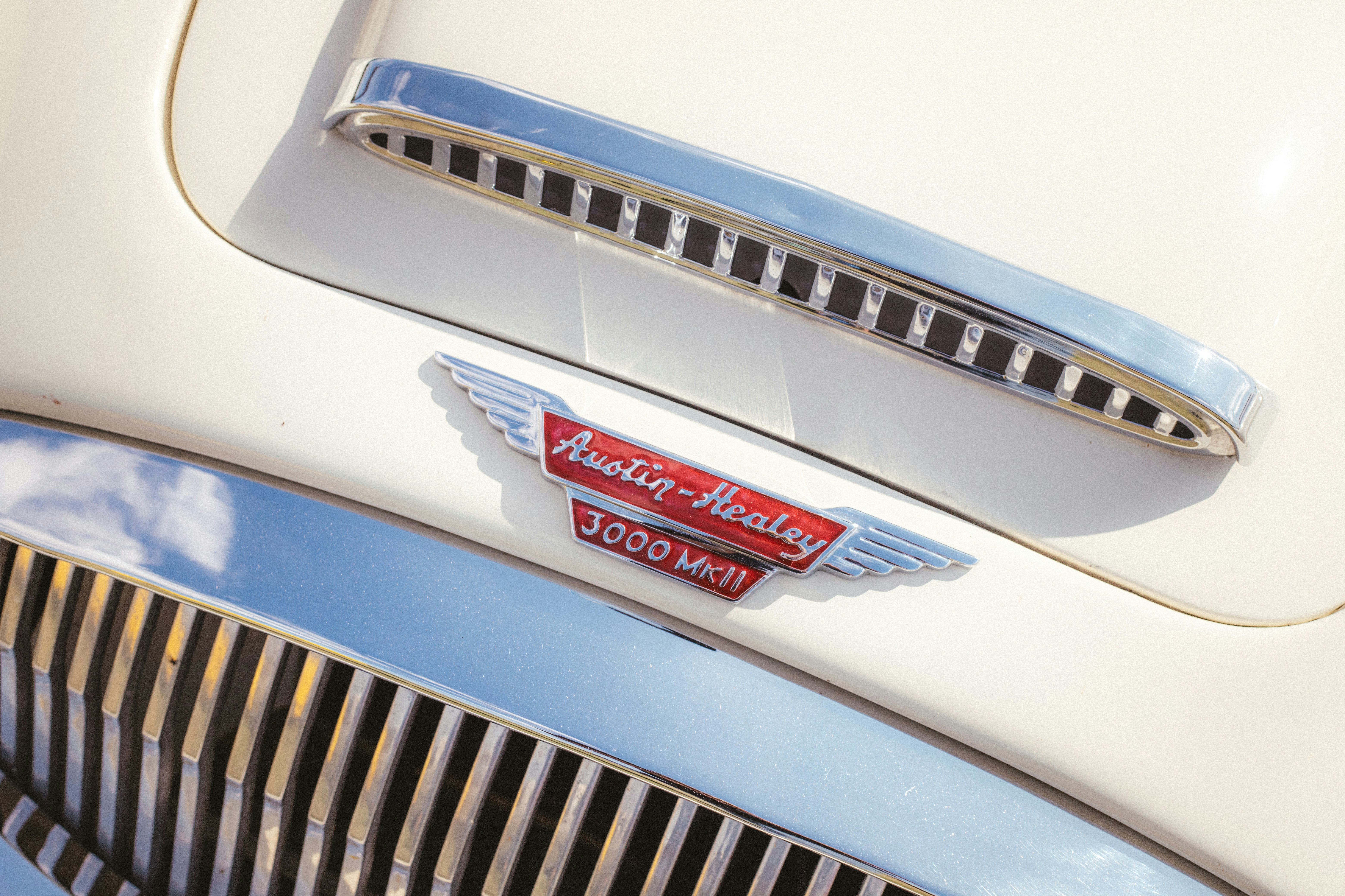 Hood Emblem Radiance: Vintage Austin-Healey Crest on Sunlit Grille
