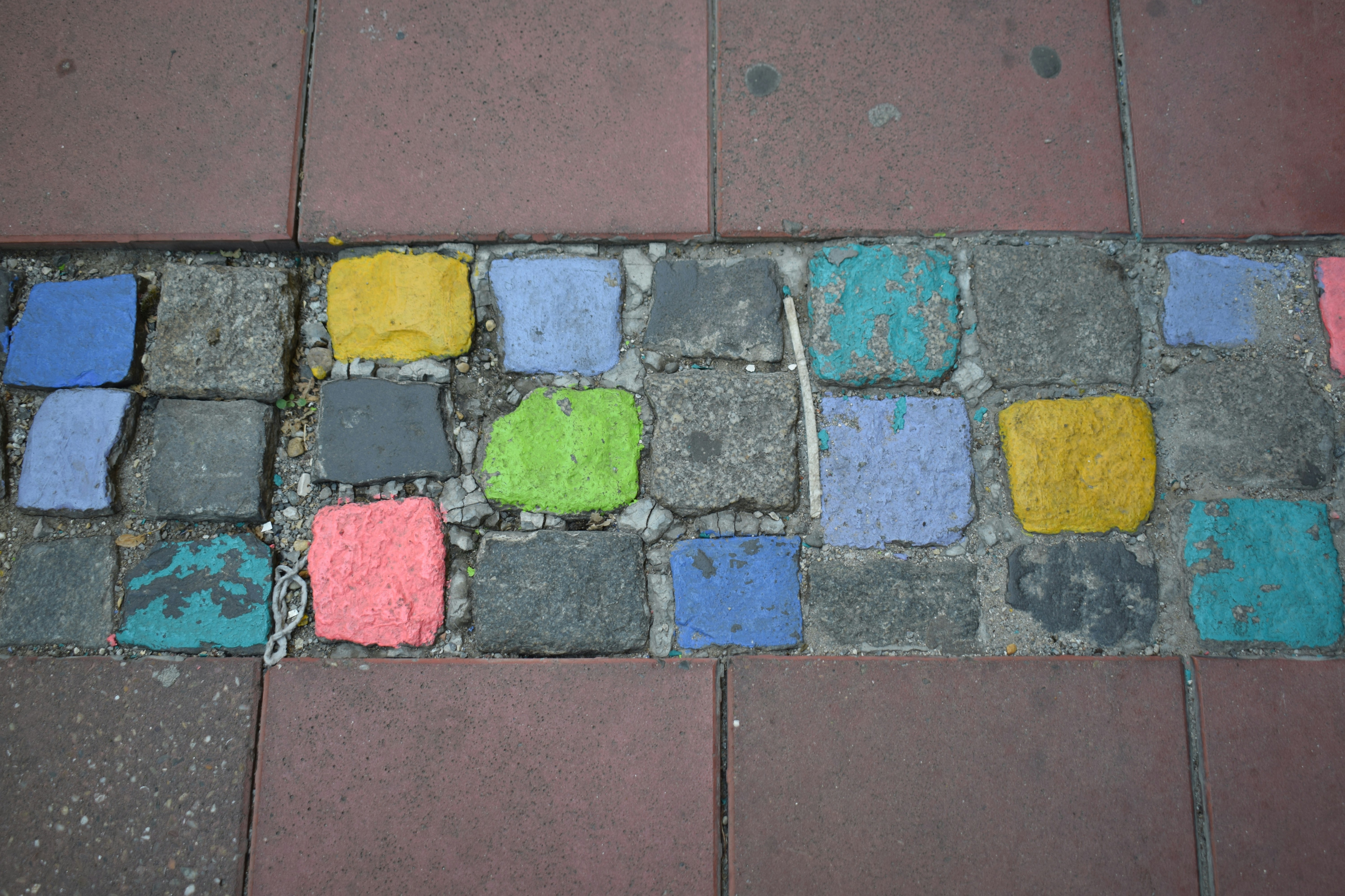 Chromatic Cobblestones: Painted Squares Amid Plain Pavers