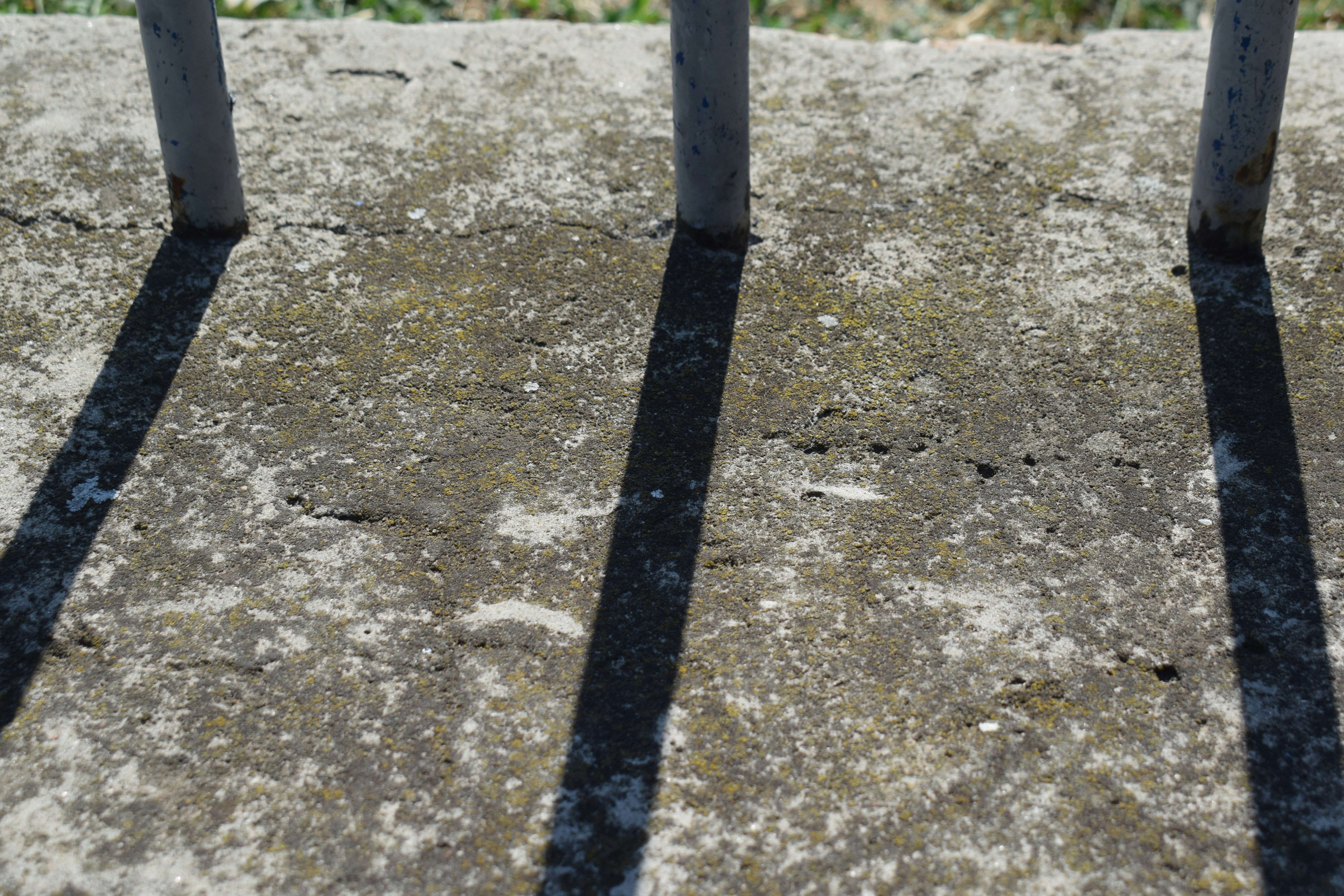 Shadowed Rails Crossing a Weathered Concrete Surface