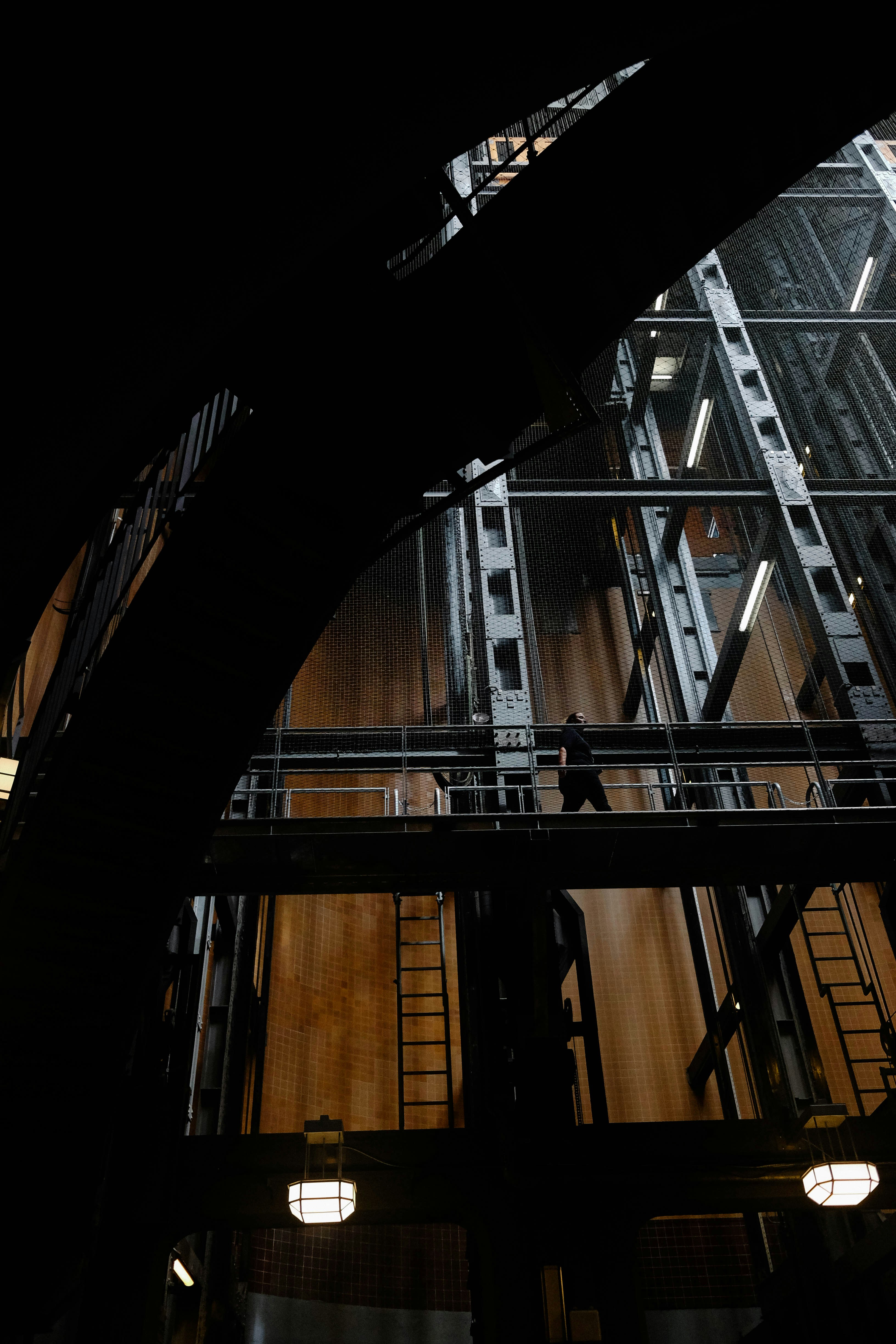 Between Steel Beams: A Lone Figure Traversing an Industrial Atrium